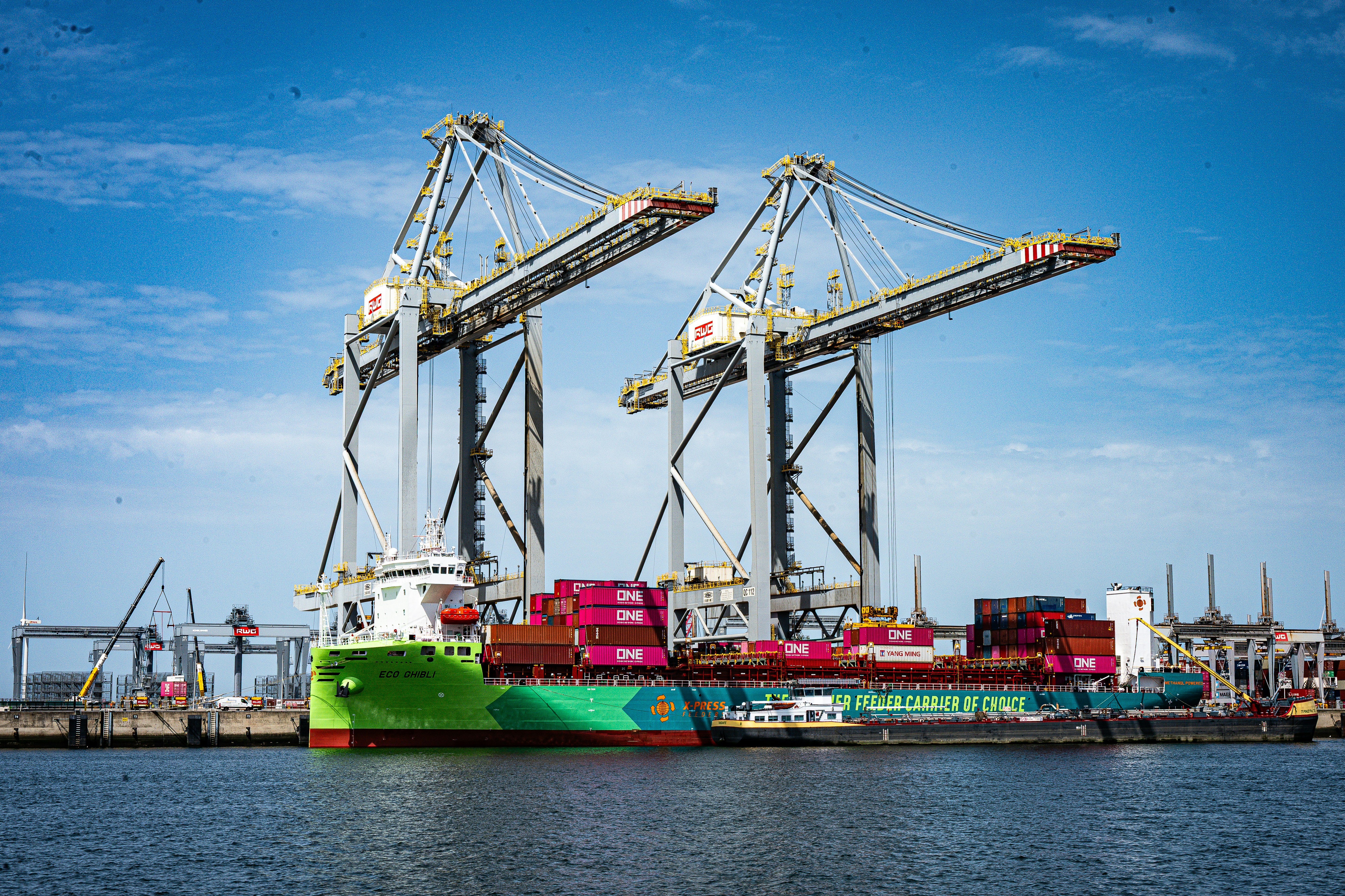 Green-decked Cargo Vessel Aligns with Towering Cranes at Dusk Harbor