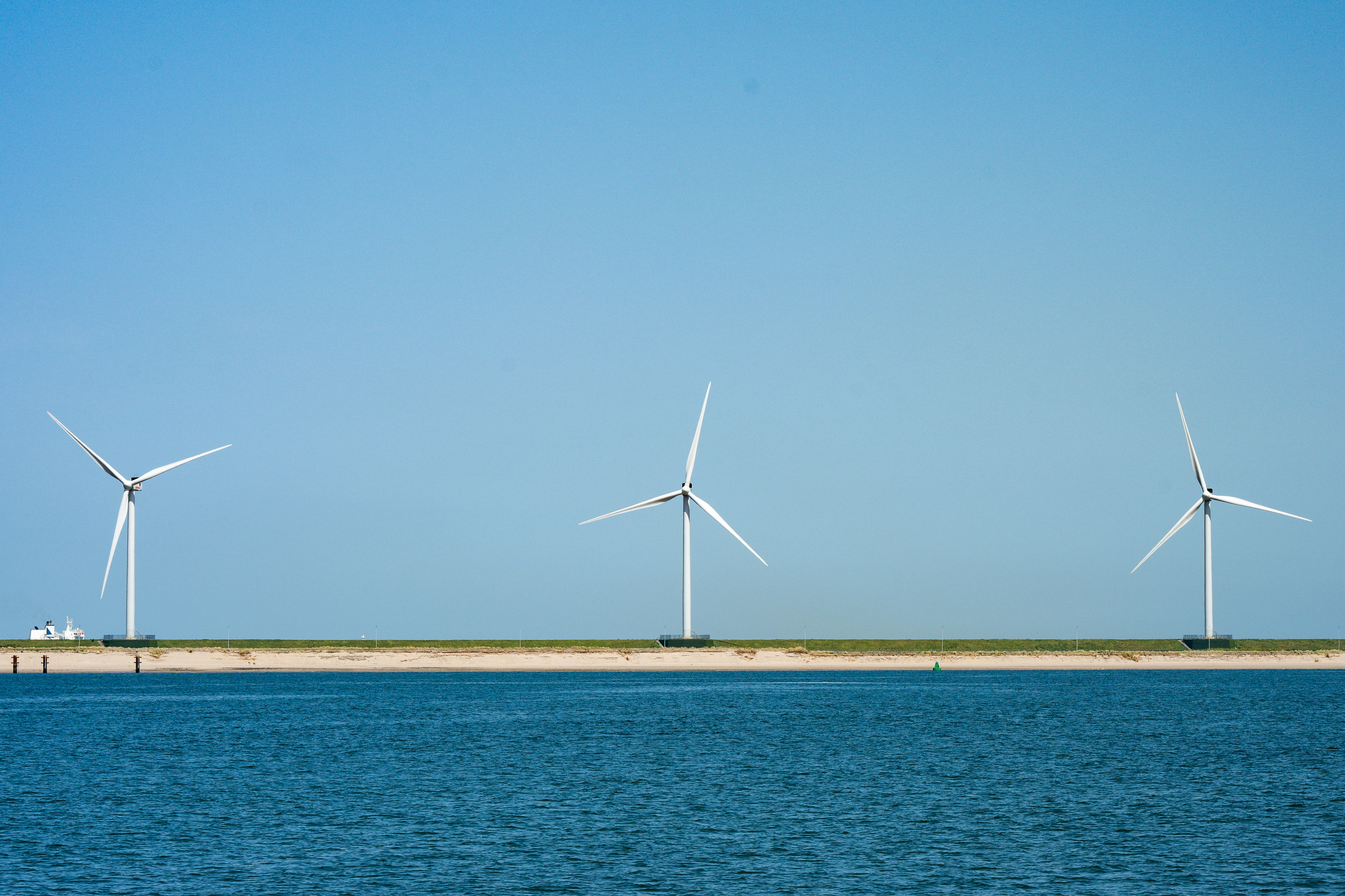 Three Wind Turbines Standing Guard Along a Seawall