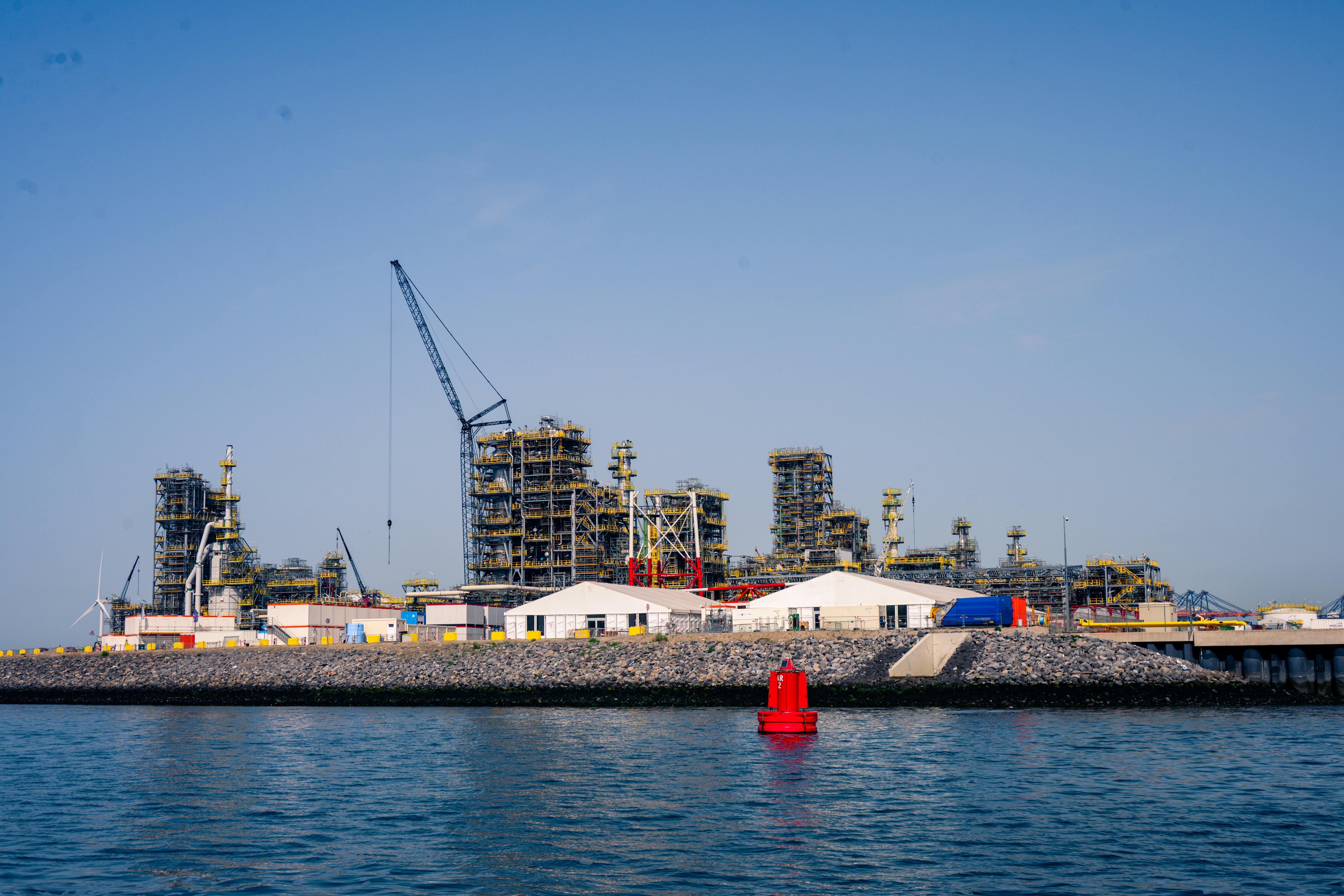 Harborworks: Concrete silhouettes and a lone red buoy against a calm inlet