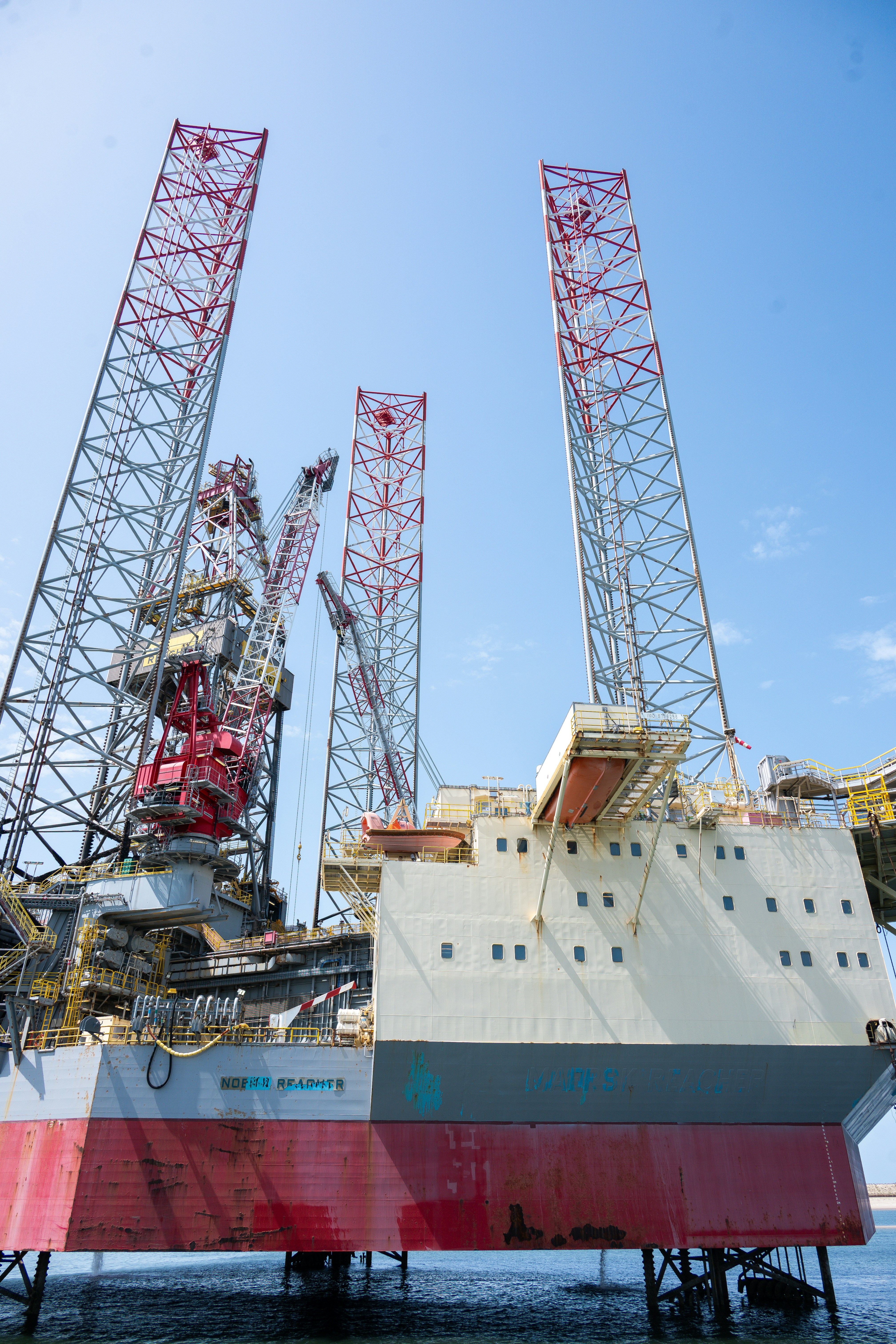 Giant offshore rig rising above turquoise seas under a crisp blue sky