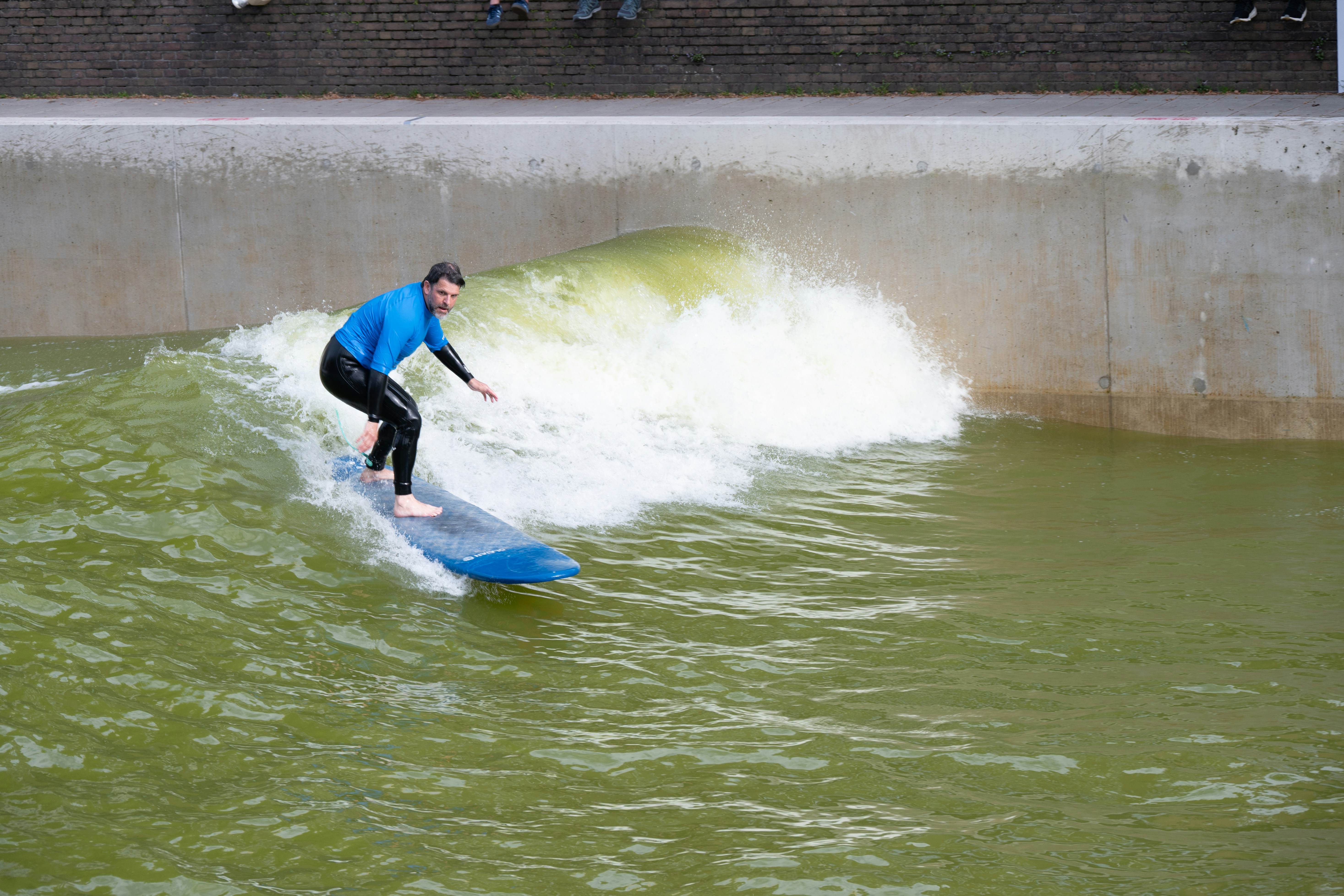 Rider in Blue Guides the Wave through the Concrete Channel
