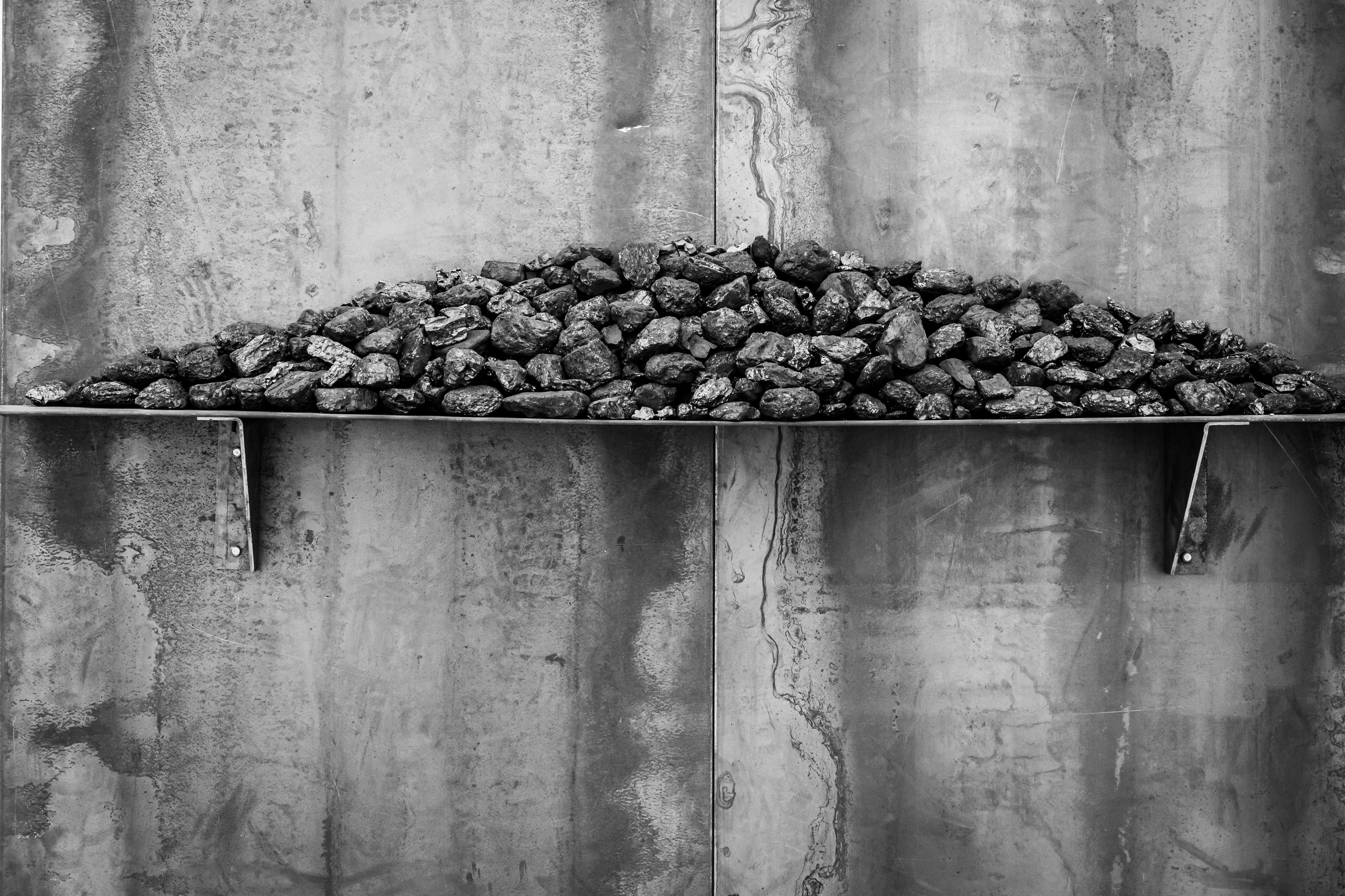 Industrial Monolith: A Black-and-White Clump of Gravel on a Concrete Facade