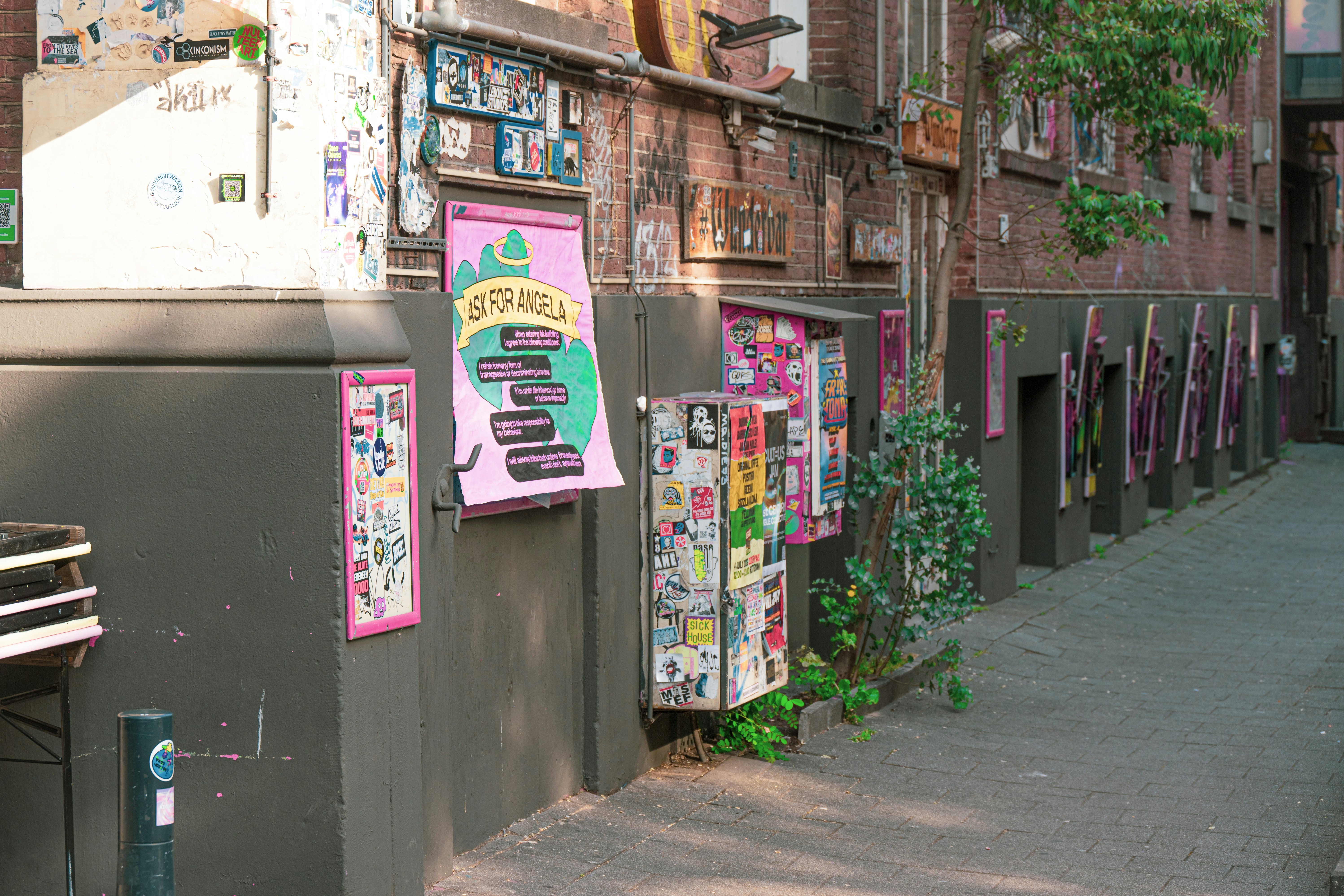 Colorful street-museum of posters and plants along a brick alley