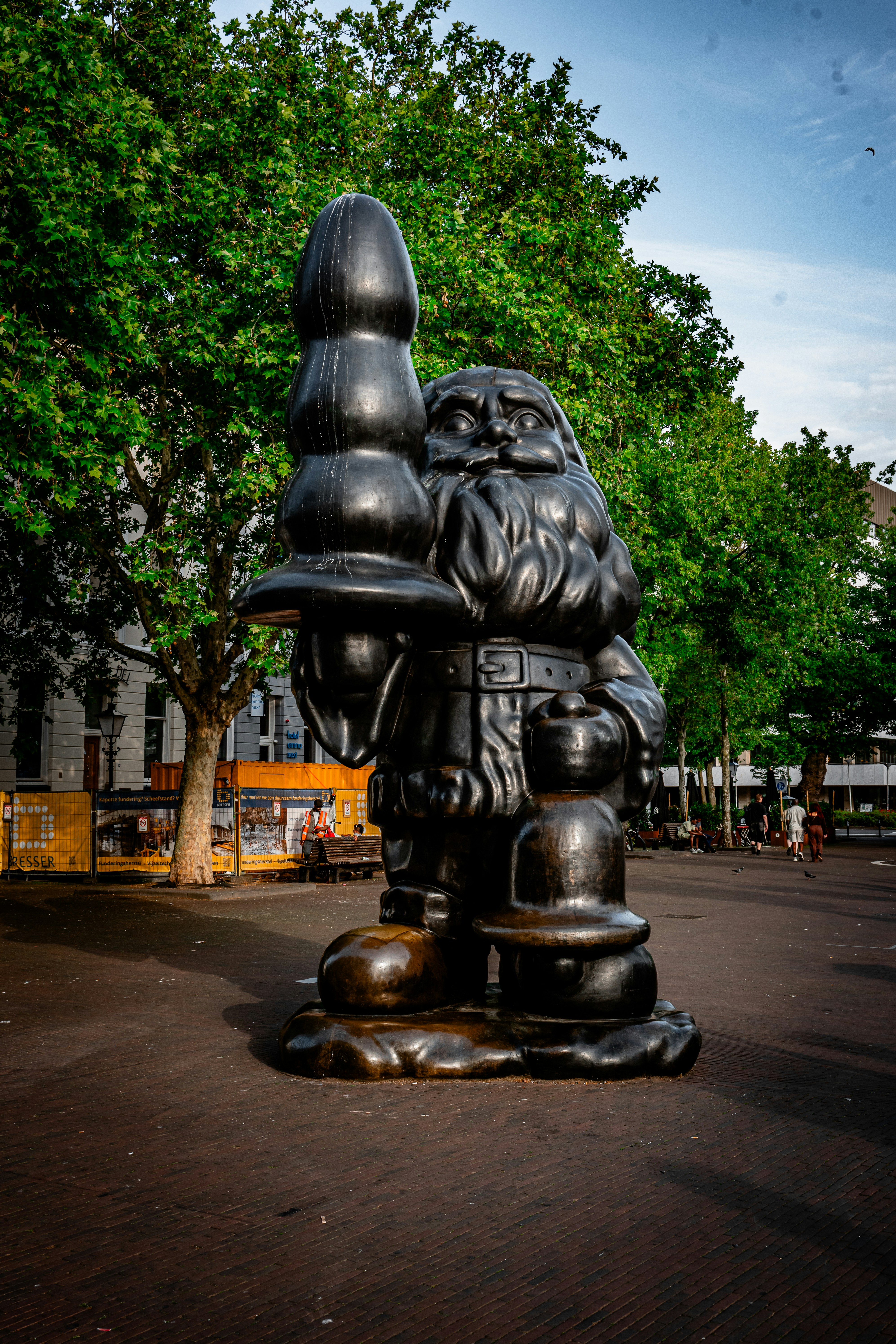 Gnomey Sentinel: A Black Statue Reaching Skyward in a City Square