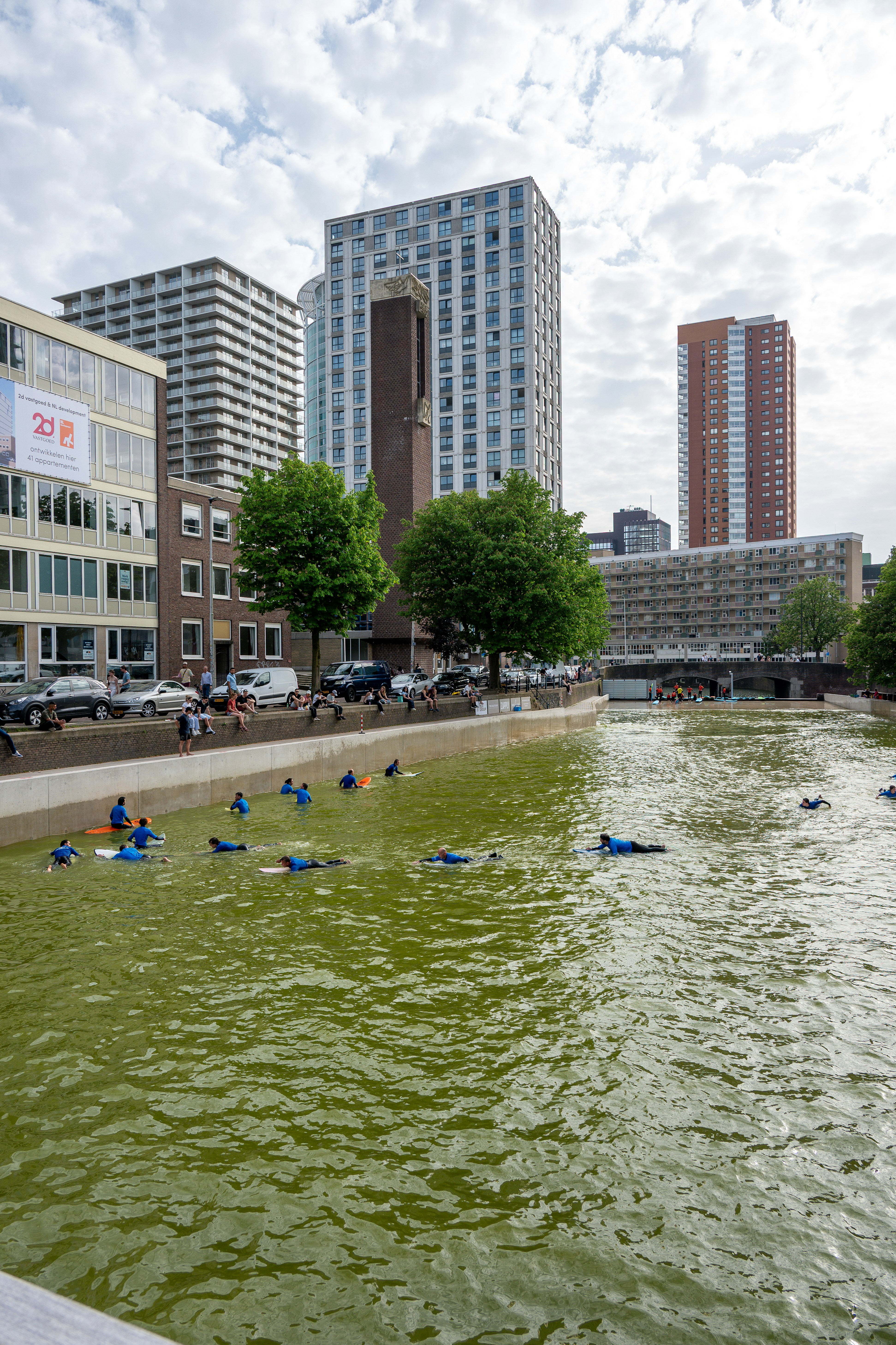 Urban Canal: Rowers, Riverside Path, and Skyward Towers