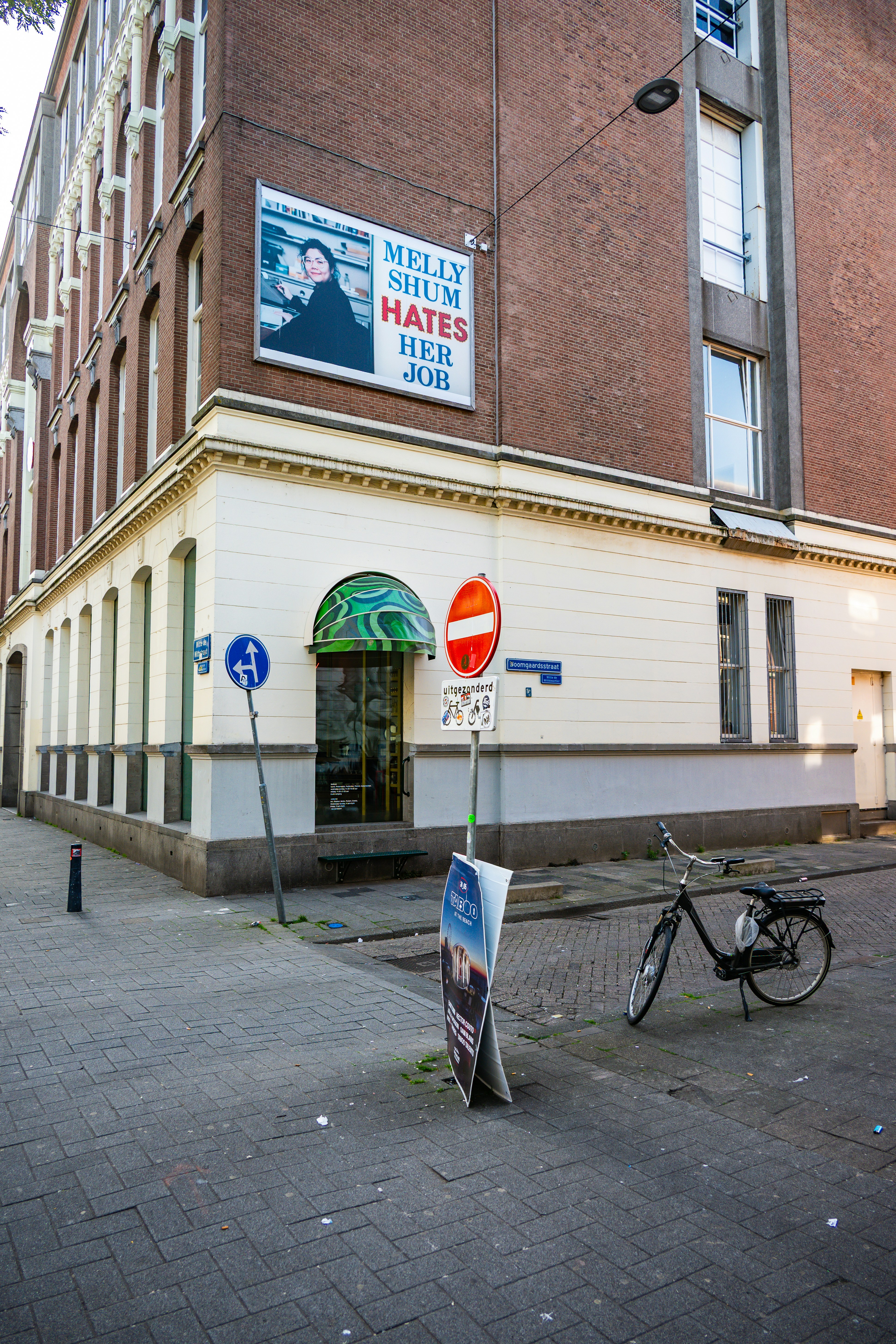 Brick Corner with Street Signage and Cyclist Leaning Against the Wall
