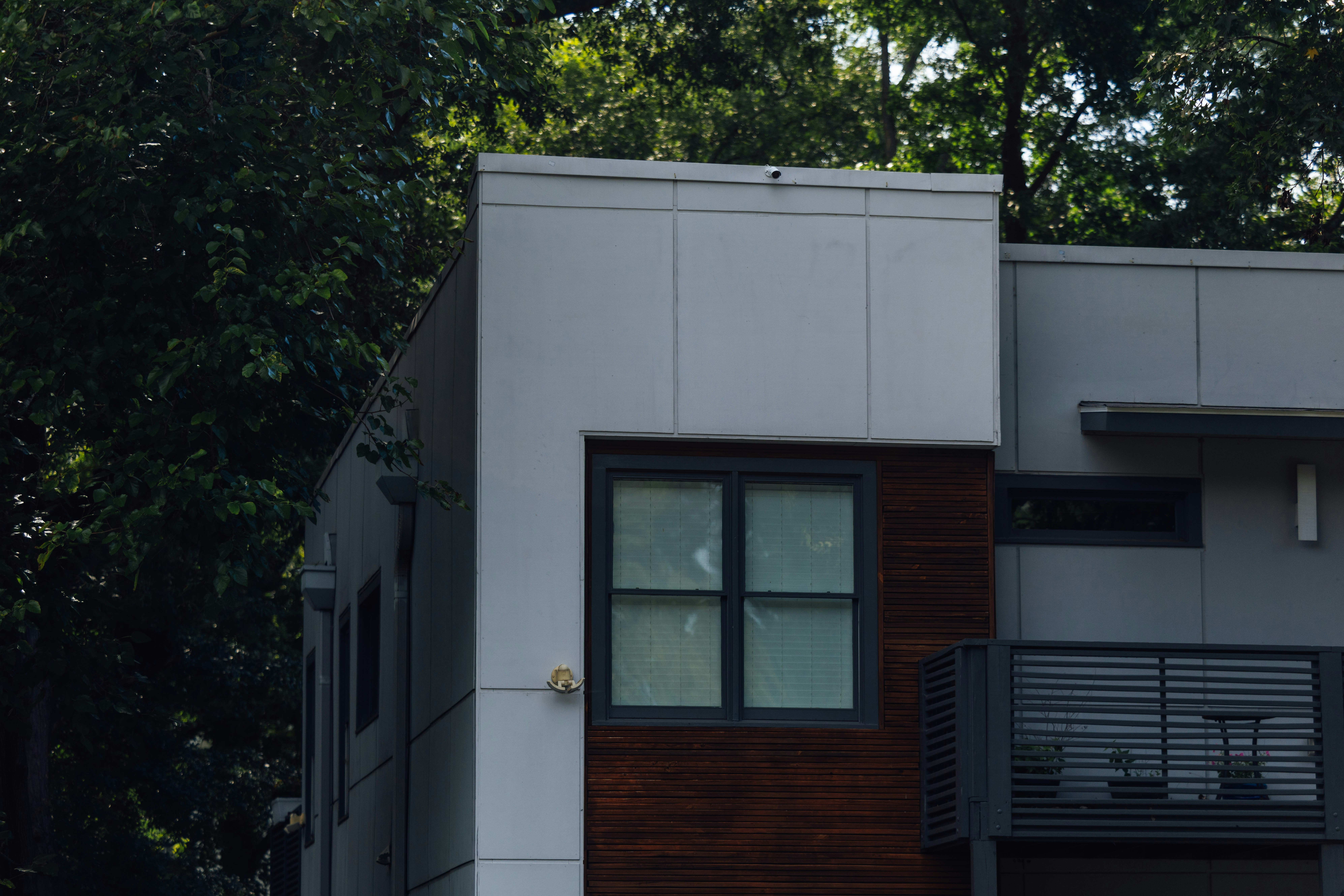 Concrete-clad building corner with a wooden panel accent and a single window; a calm, architectural composition emphasizing textures and line geometry.