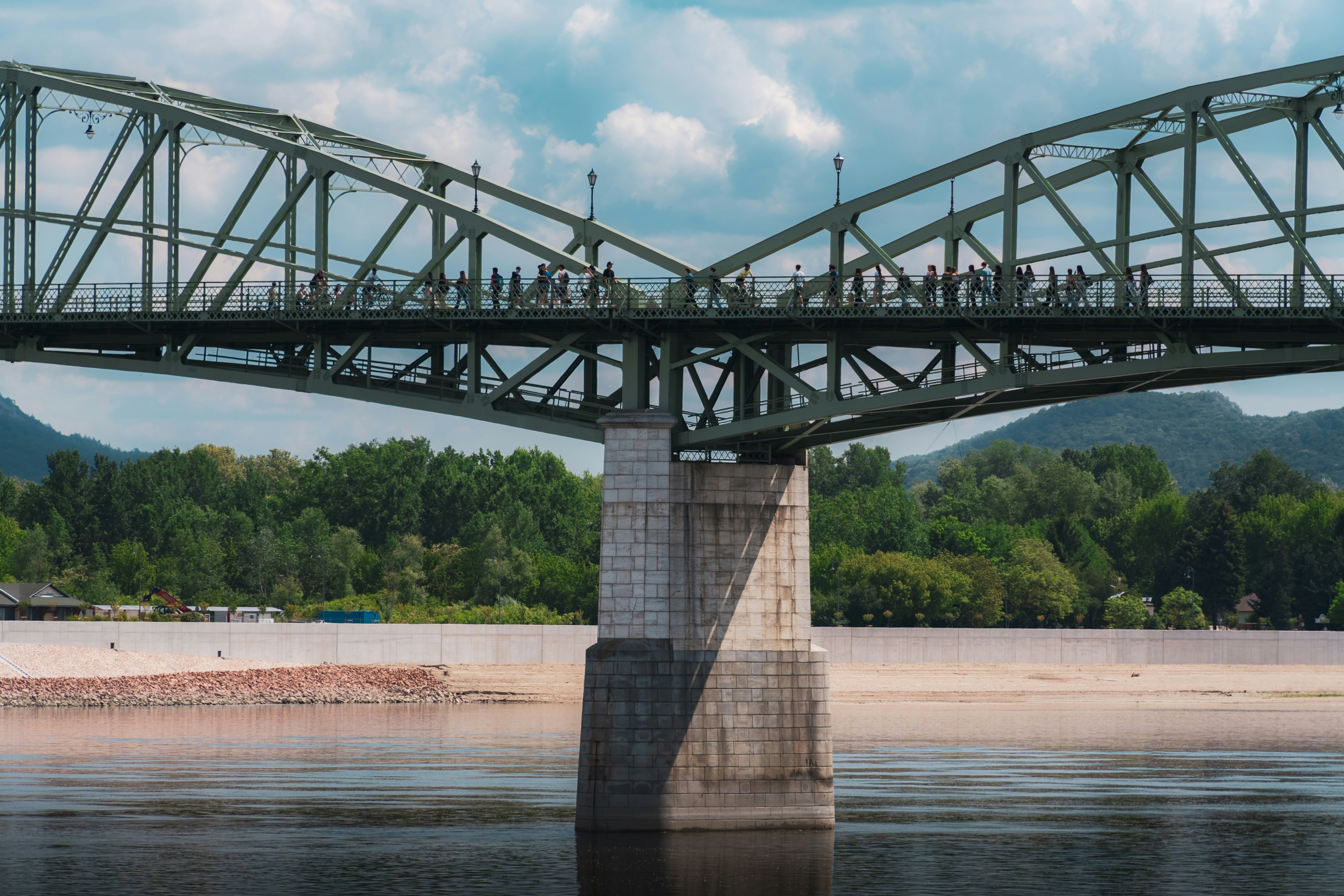 Riverside Steel: Pedestrians Crossing the Truss Bridge at Midday