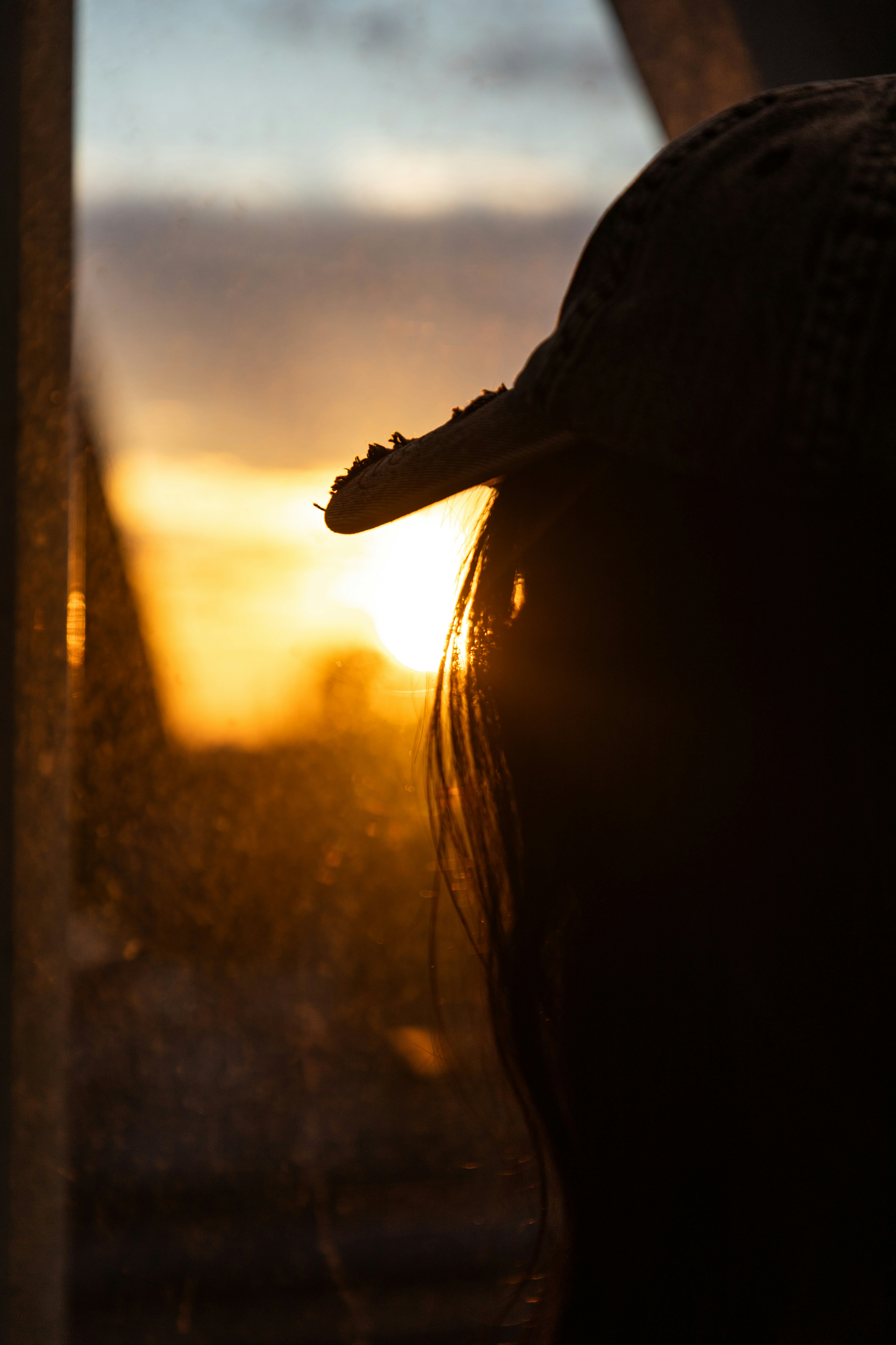 Silhouette at Sunset: A Hat-Covered Moment Framed by Golden Light