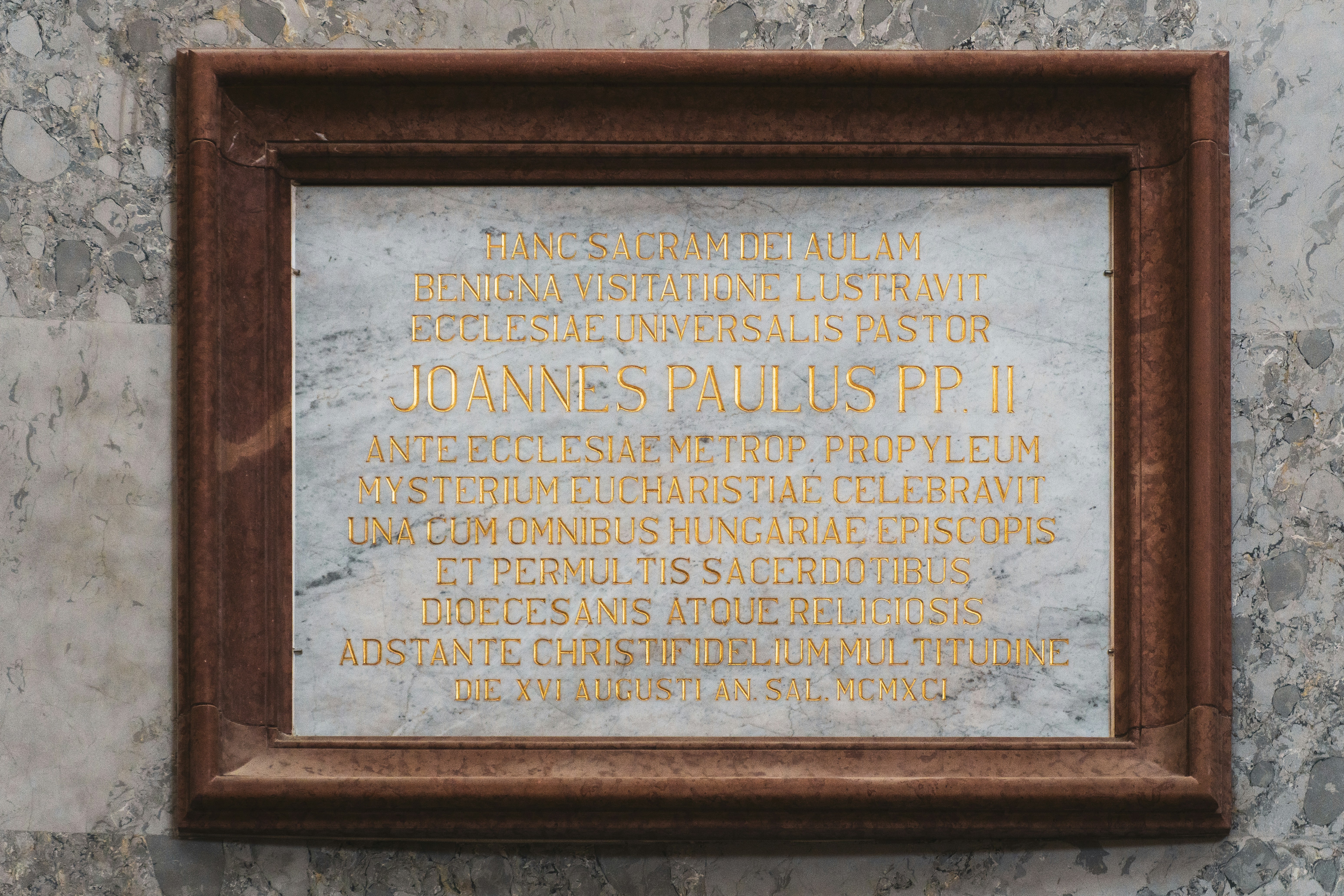 Inscribed stone plaque in a wooden frame embedded in a stone wall