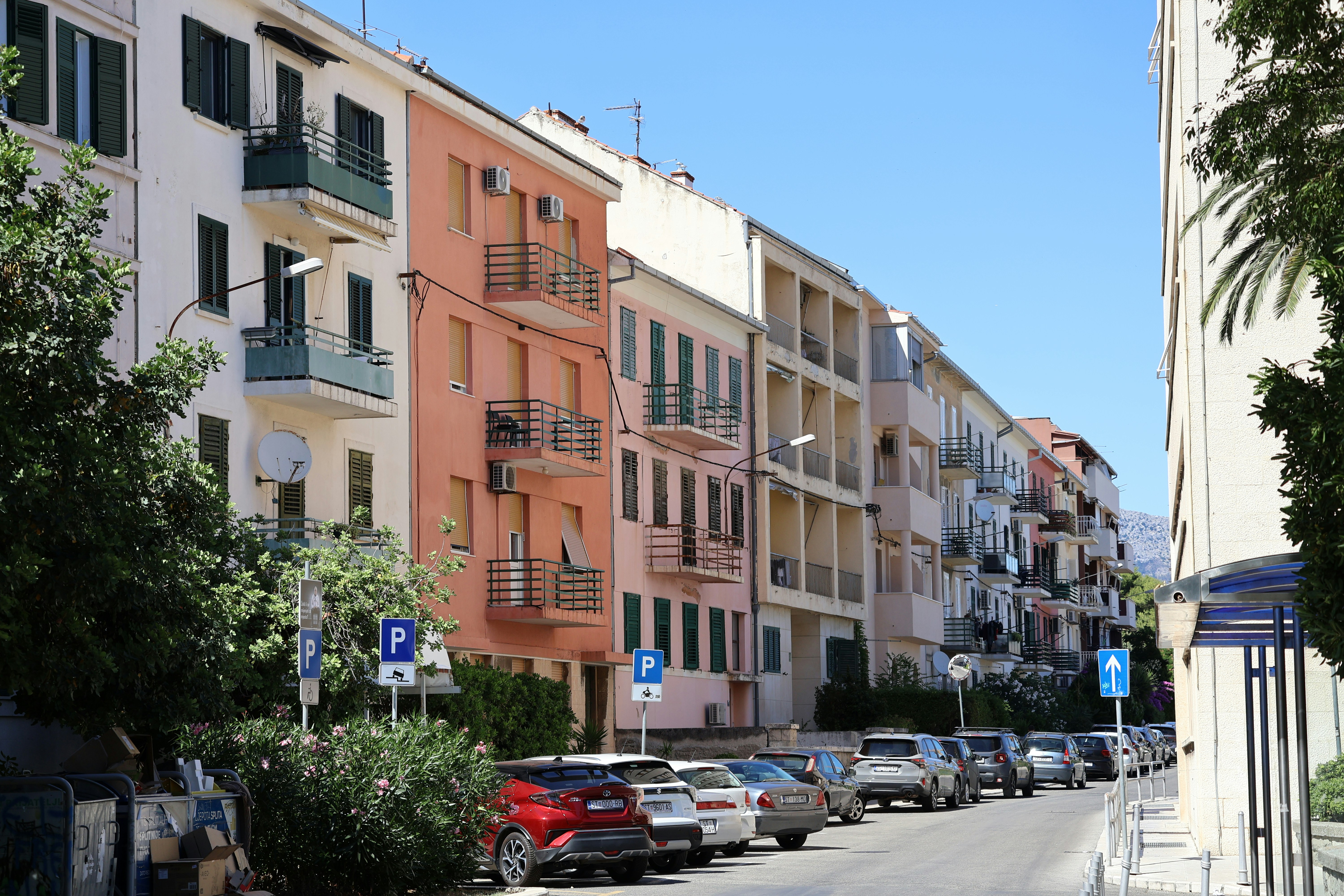 Colorful Mediterranean Street: Facades, Balconies, and Parked Cars
