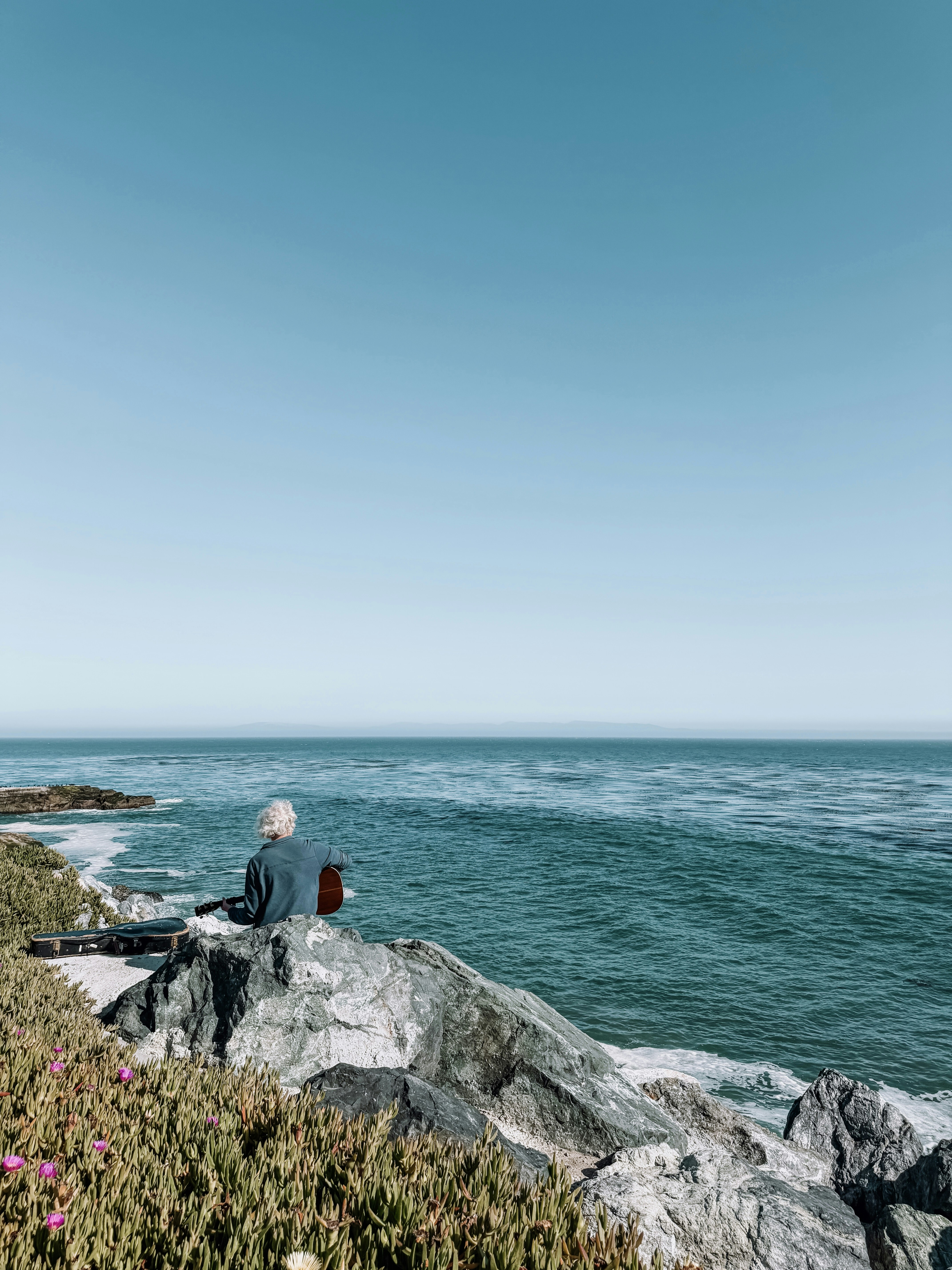 Seated silhouette against a horizon of sea and rock