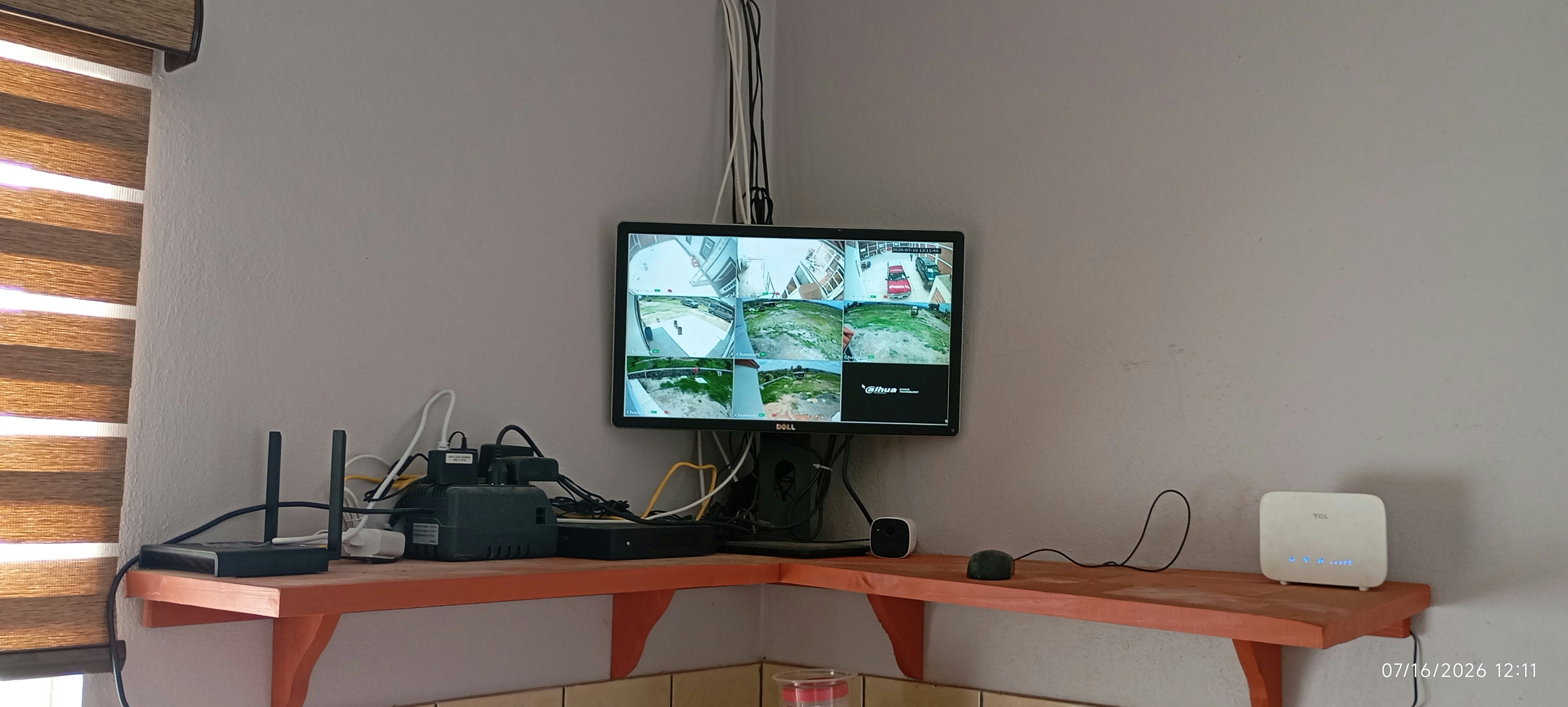 Corner Tech Hub: A Wall-Mounted Monitor Surrounded by Networking Gear