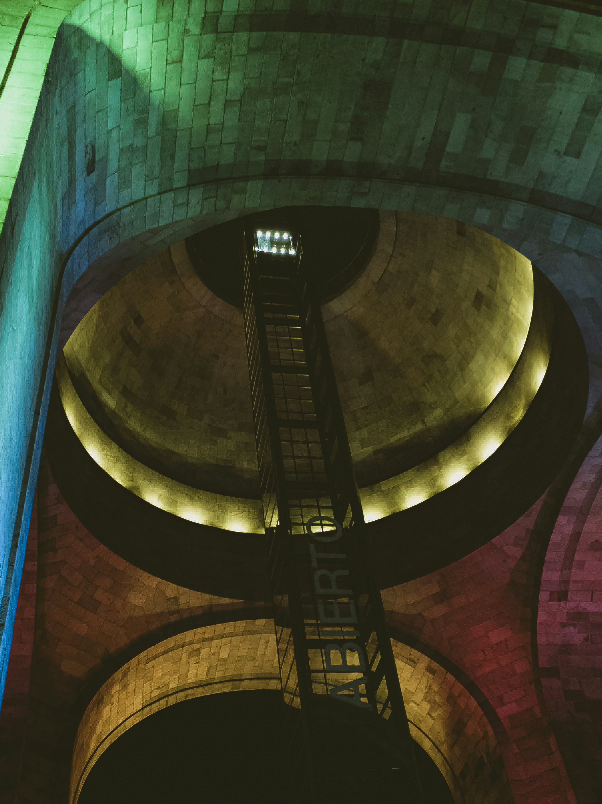 Colored Spiral: Neon-lit Staircase Ascending the Circular Atrium