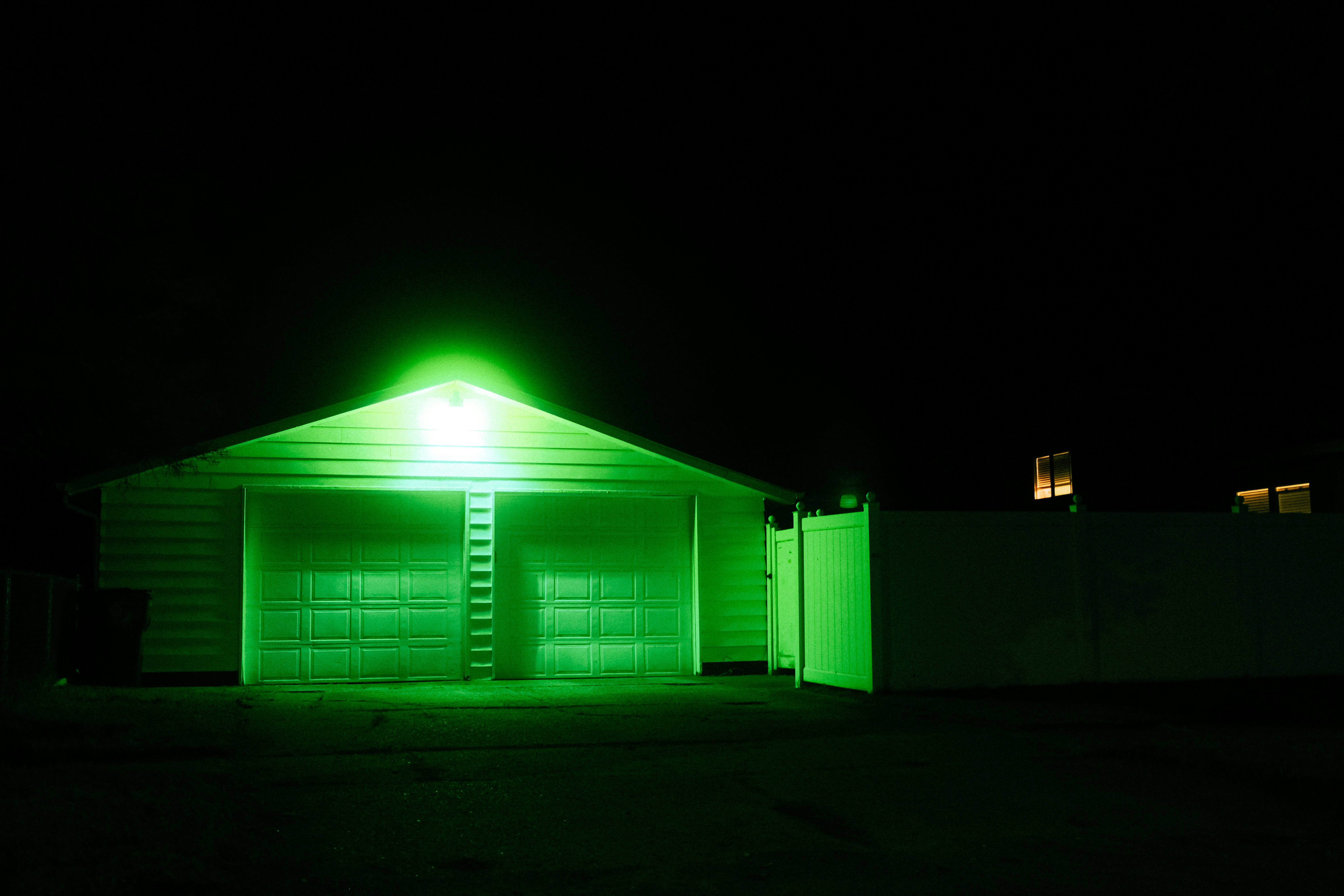 A garage illuminated by a bright green light at night.