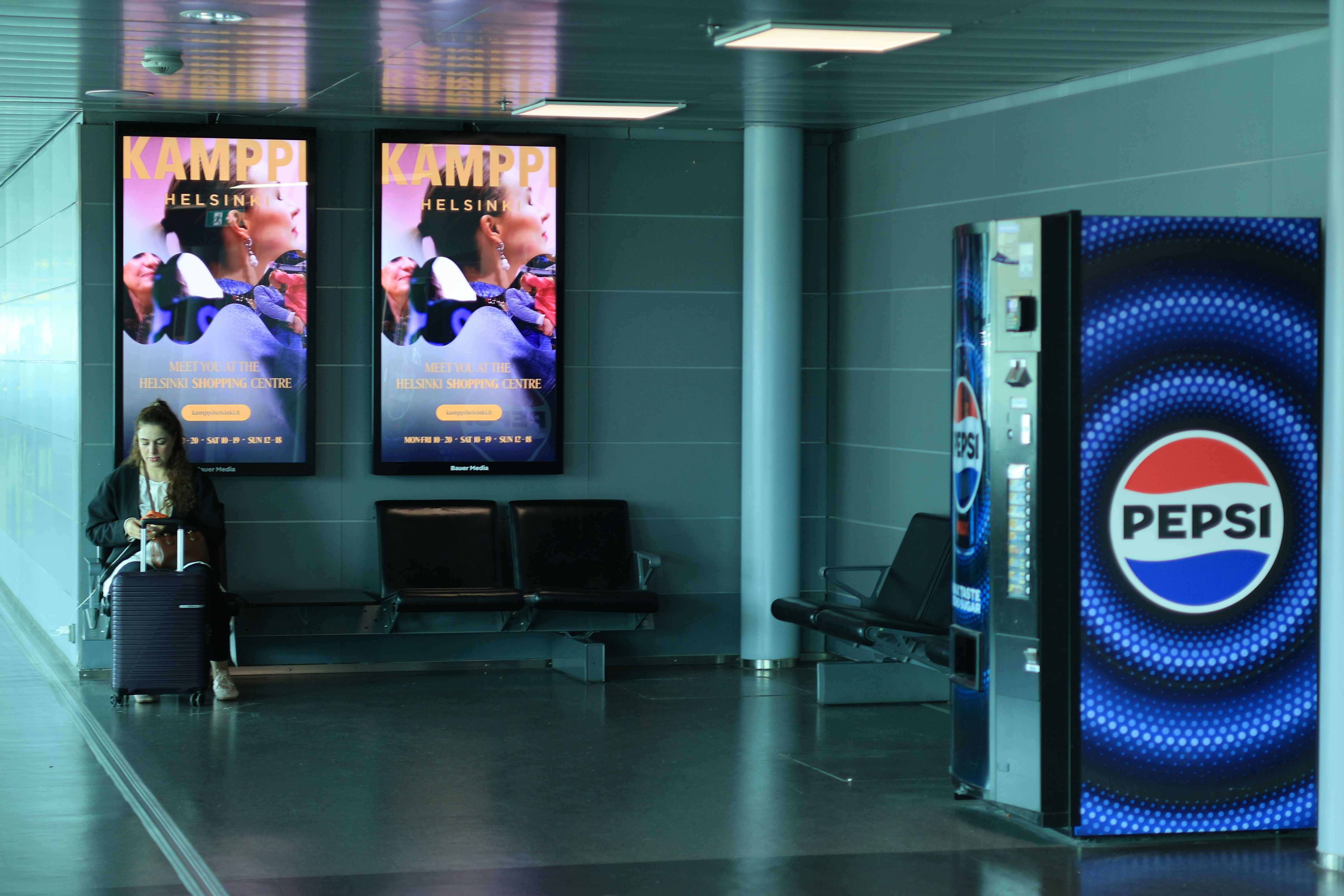 Quiet Transit: A Passenger with a Suitcase by the Pepsi Vending Shelf