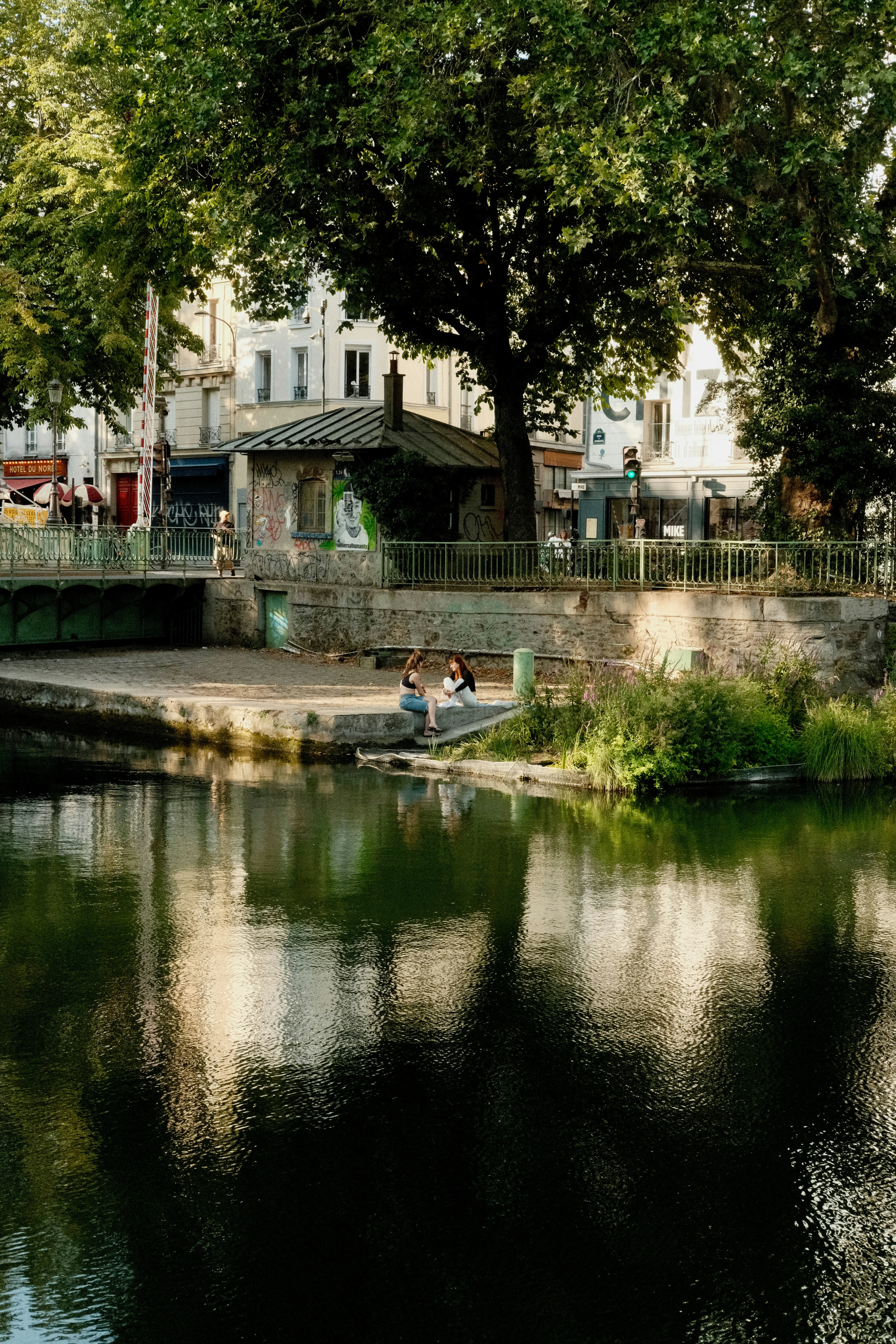 Two friends by the riverside under dappled shade