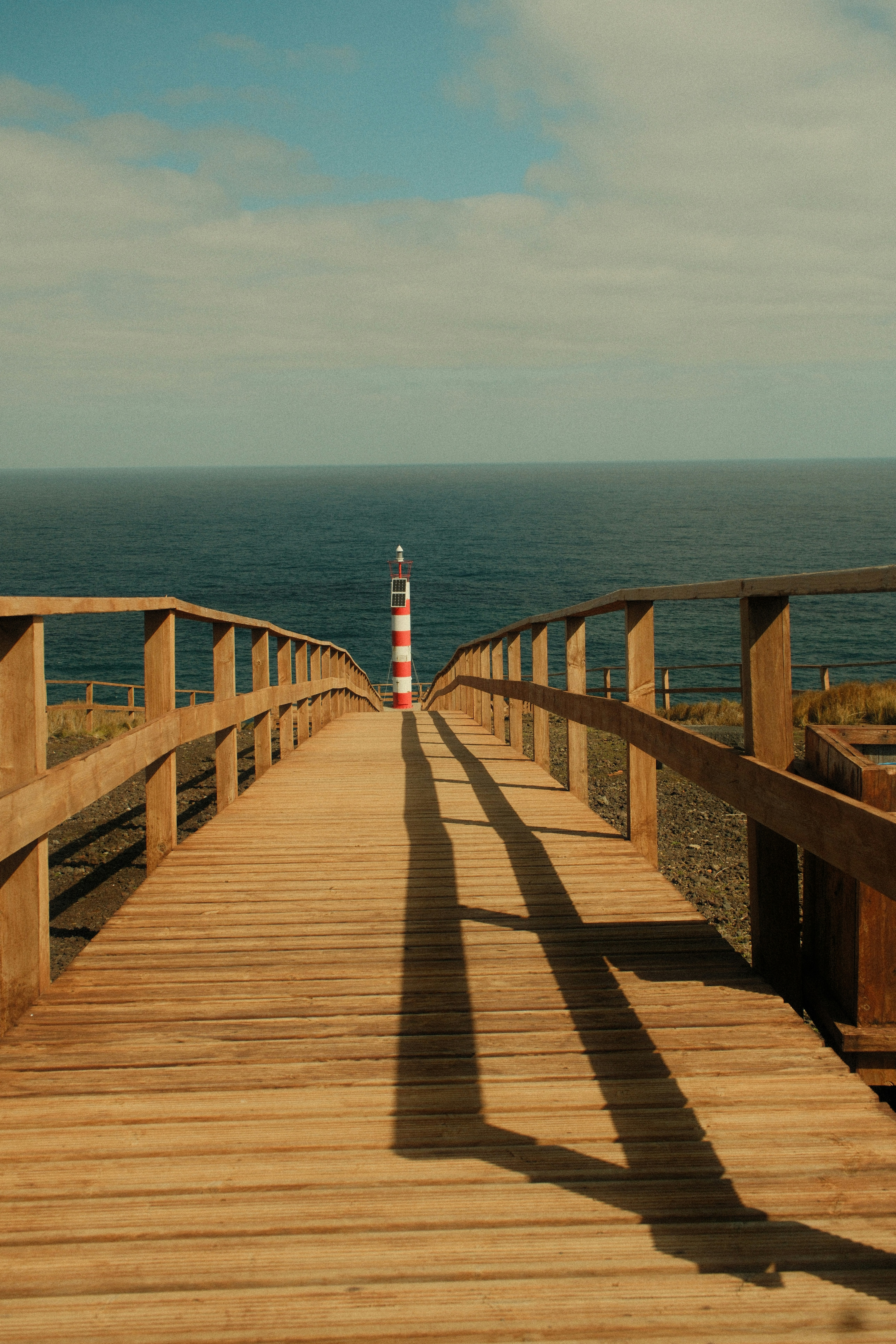 Path to the Sea: A wooden boardwalk Leading to a Lone Striped Beacon