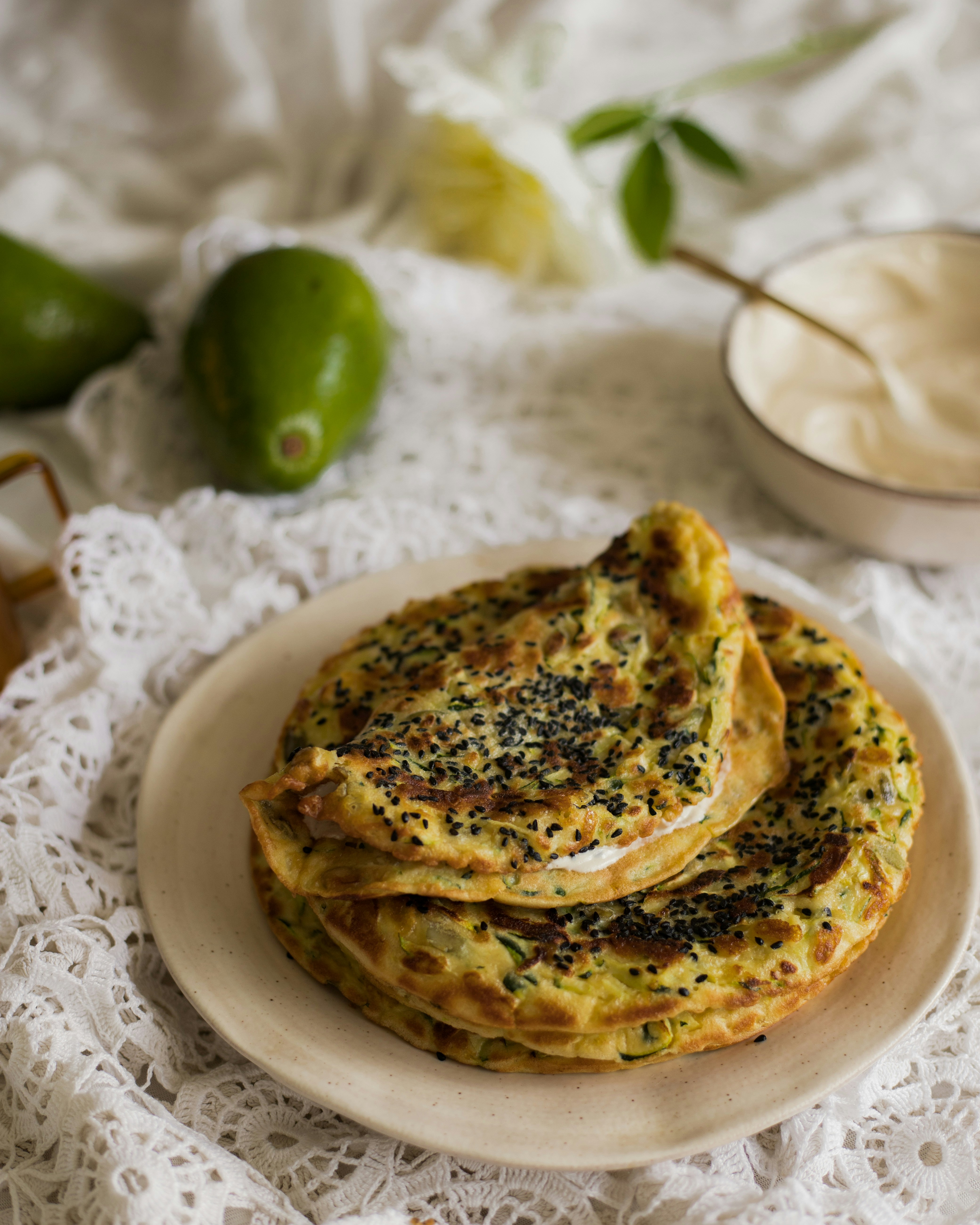 Heritage puff pastries crowned with sesame and herbs on a lace-draped plate