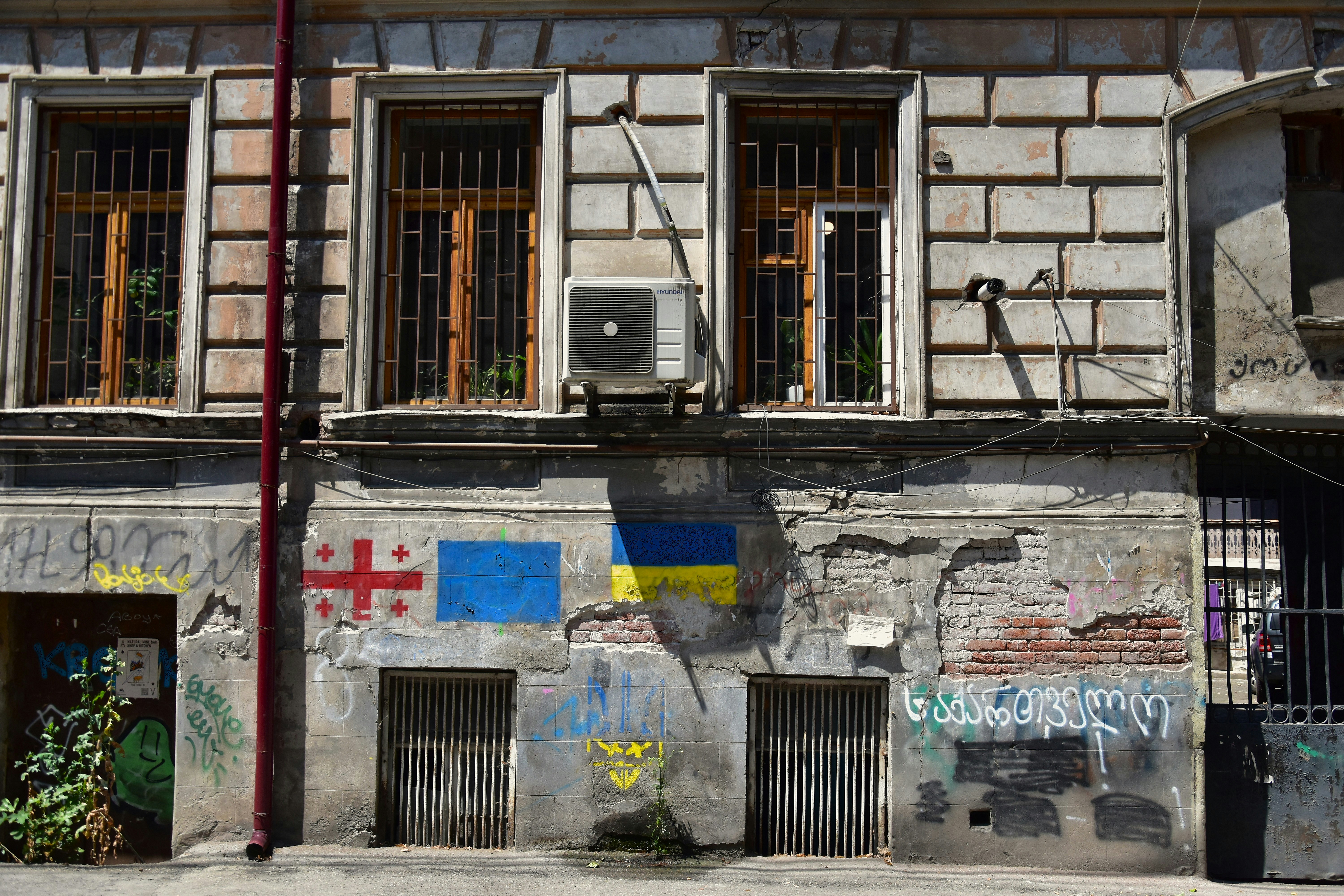 Graffiti-Fenced Facade: Windows, Air Conditioner, and Urban Decay