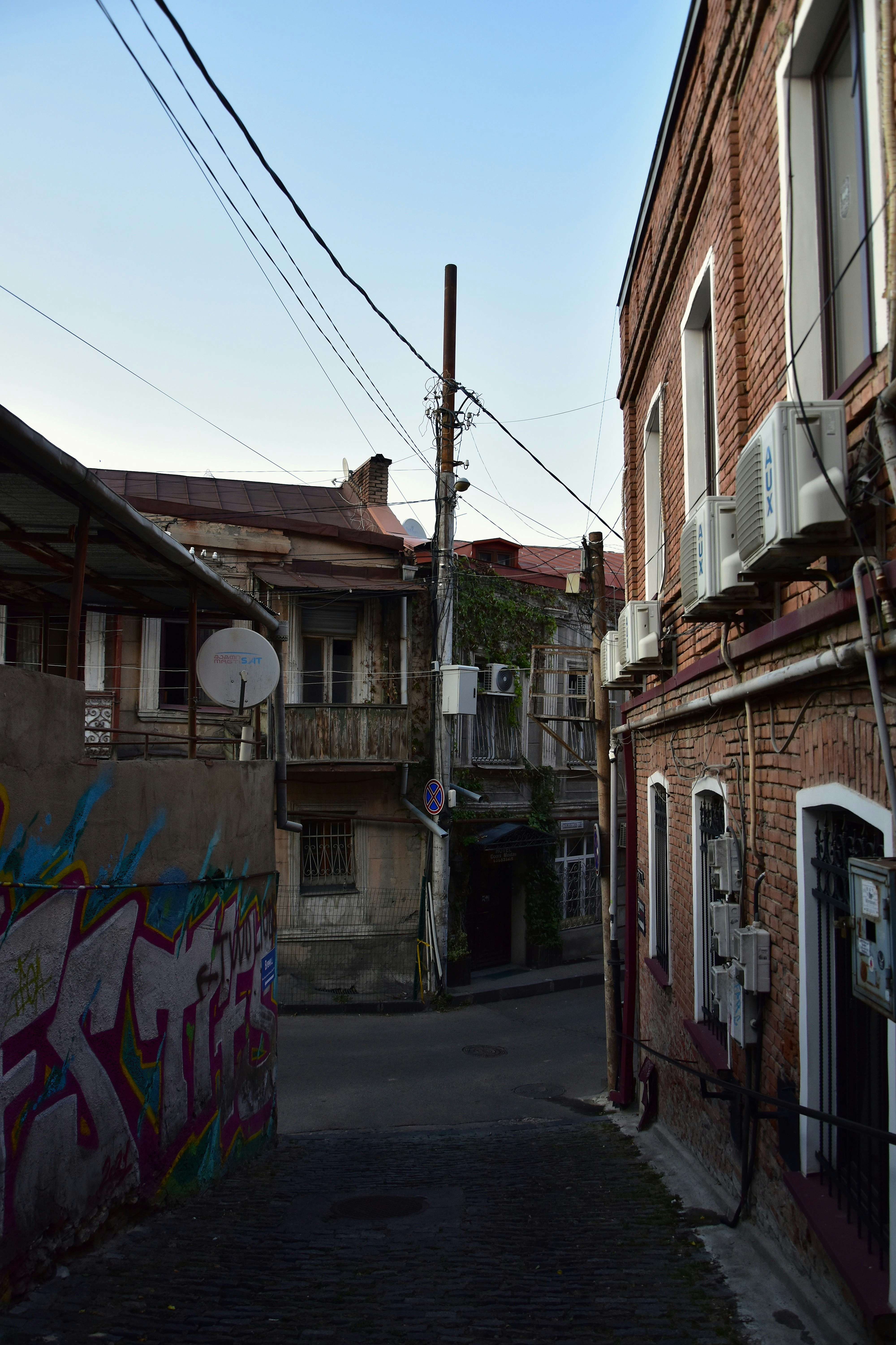 Narrow Alleyway Between Brick Facades Under Clear Sky