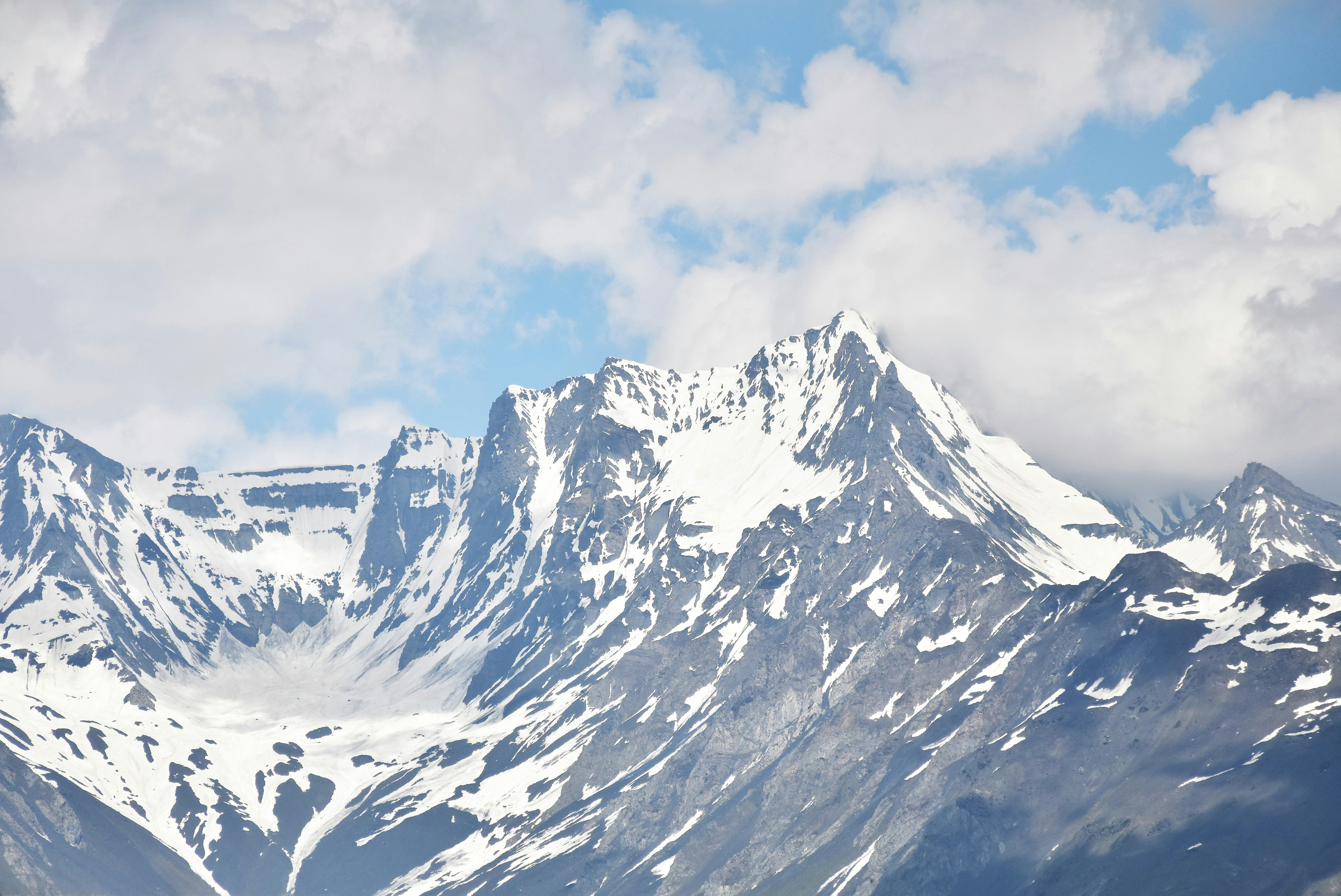 Sharp alpine silhouettes against a bright sky with snow-blanketed summits and rugged ridges in the foreground. A pristine mountain scene emphasizing texture and contrast.