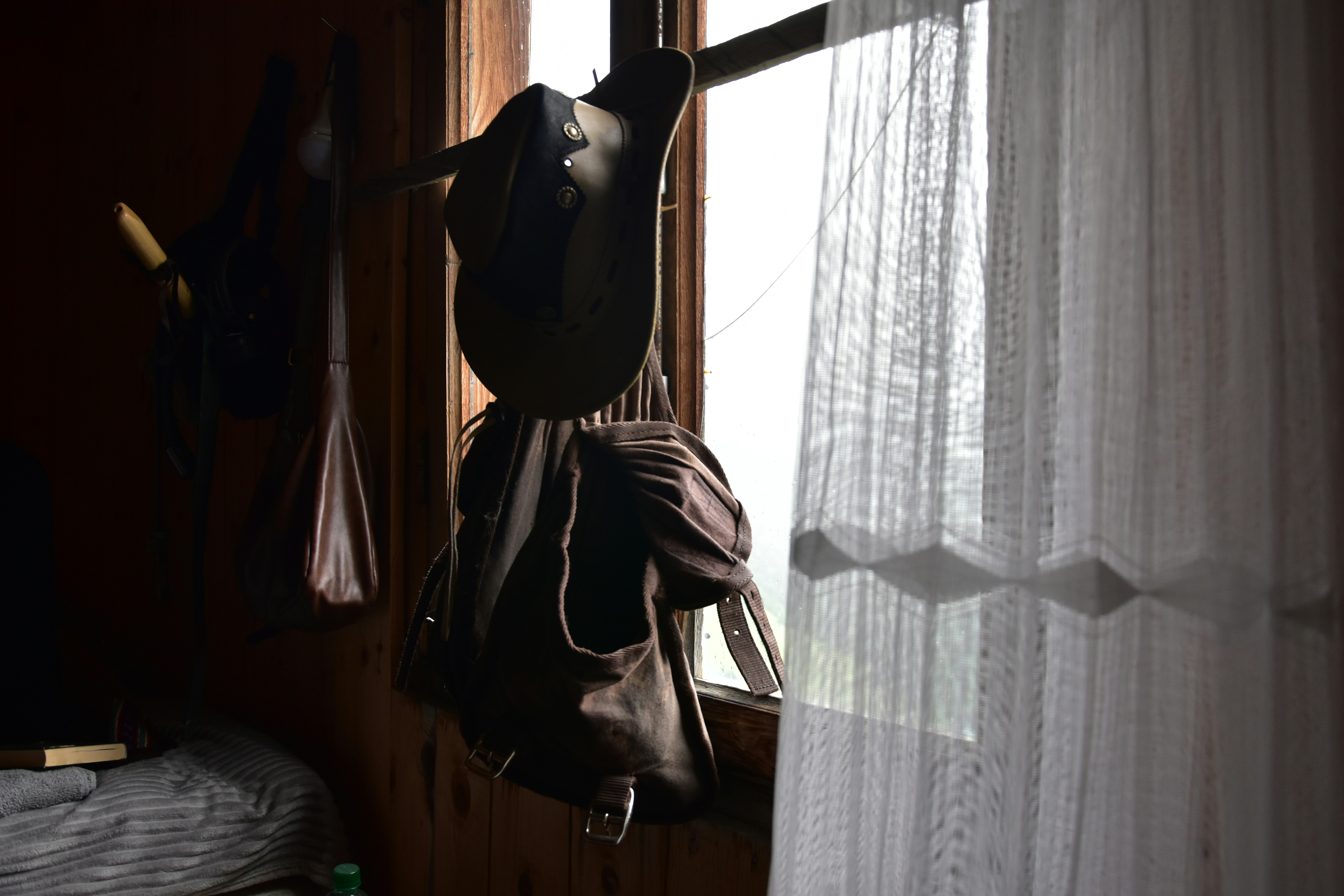 Hanging gear by a sunlit window in a dim cabin