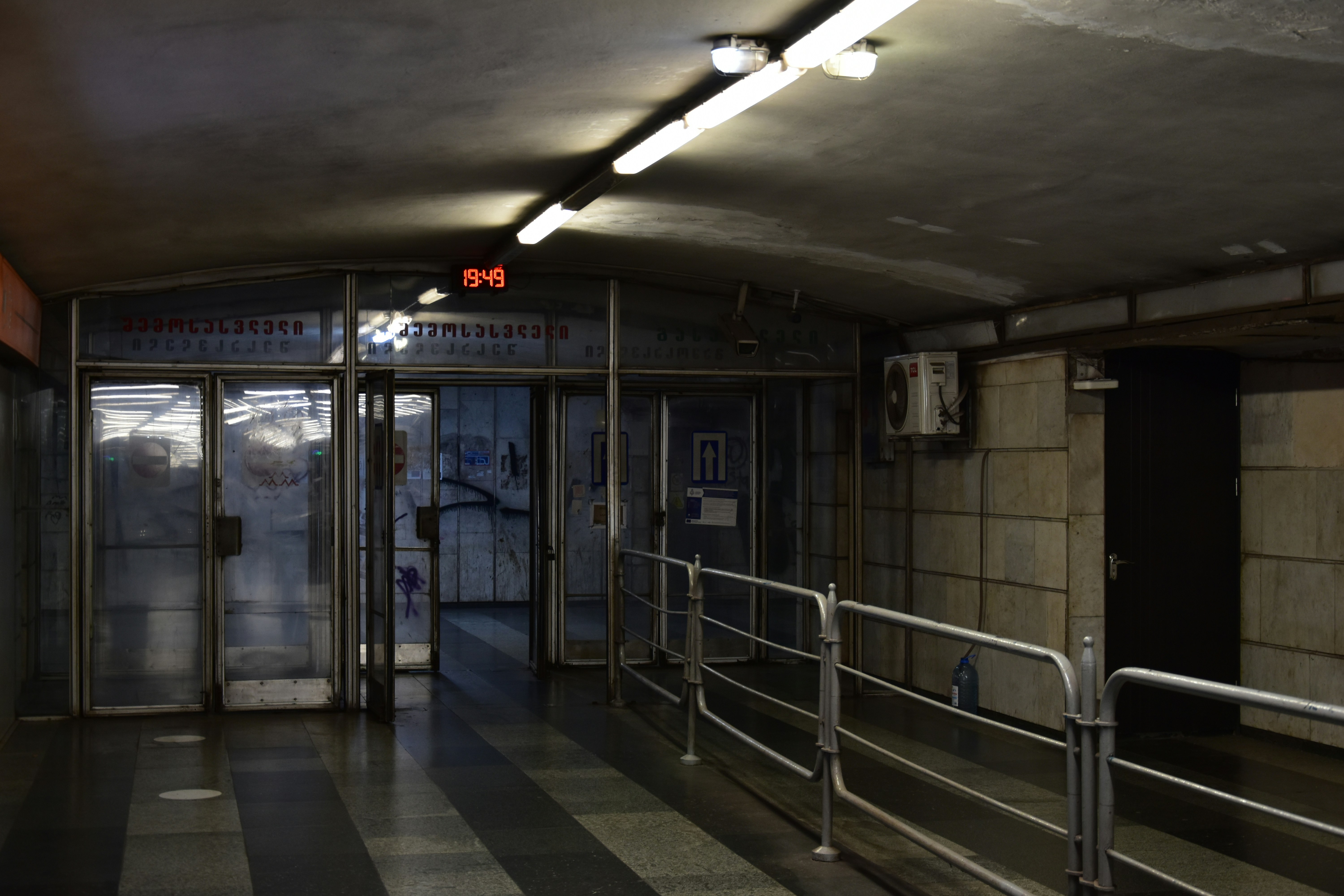Dimly lit underground passage with glass doors and a ramp
