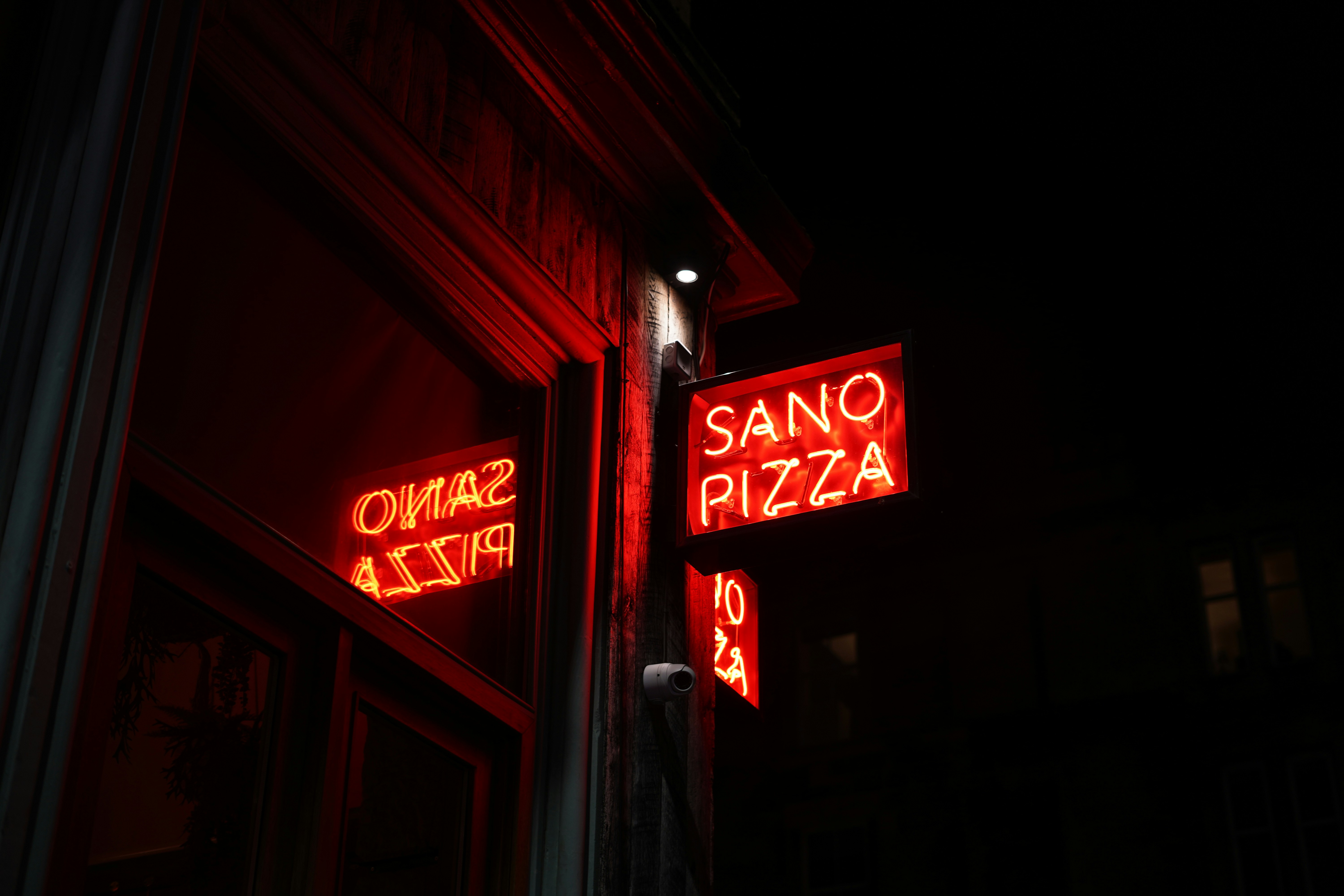 Neon Echo: Red Signage Reflections on a Dim Corner