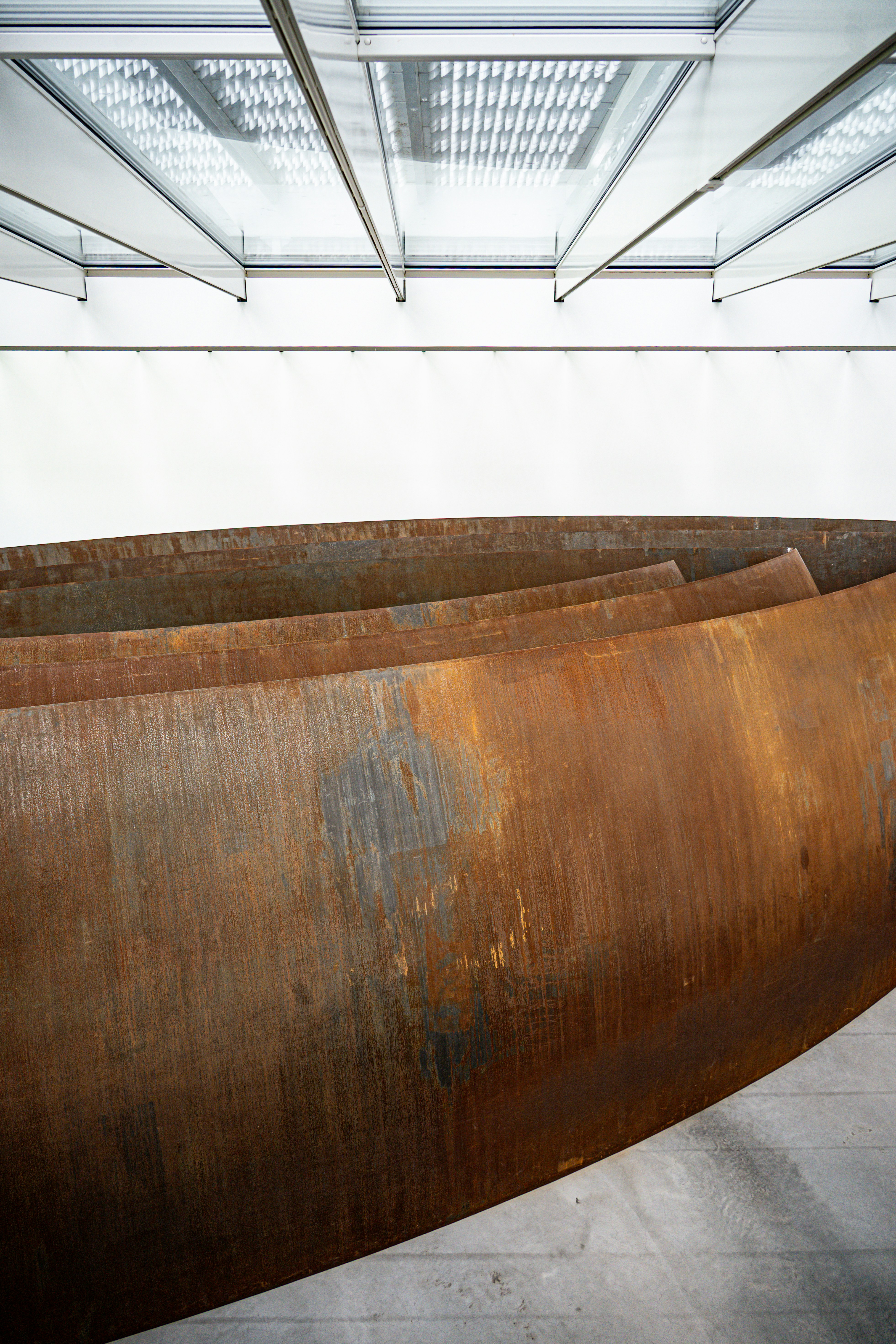 Industrial arc: rusted stainless curves beneath glass skylight