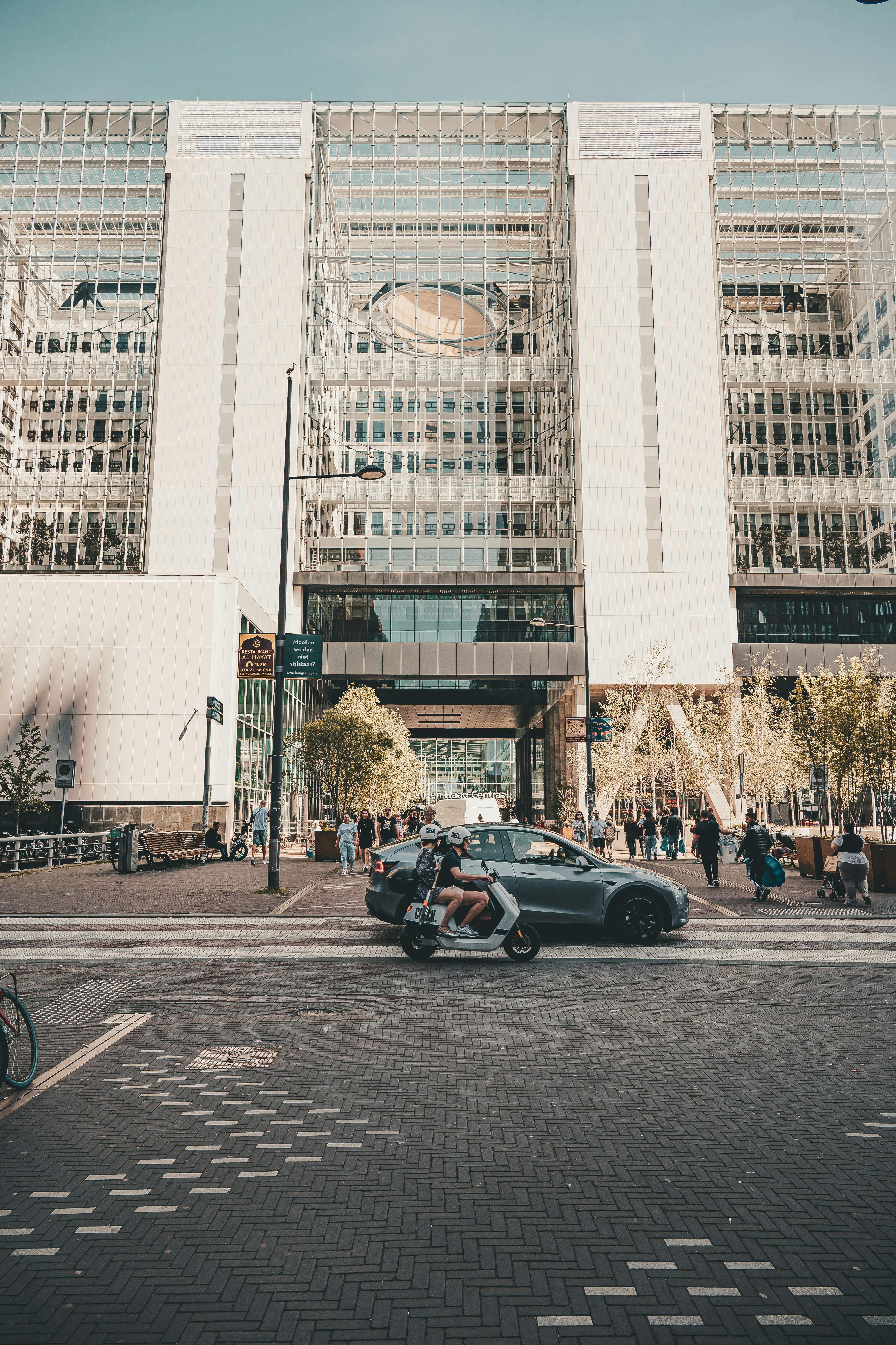 Urban Archway: Car and Scooter Pause Under a Modern Facade