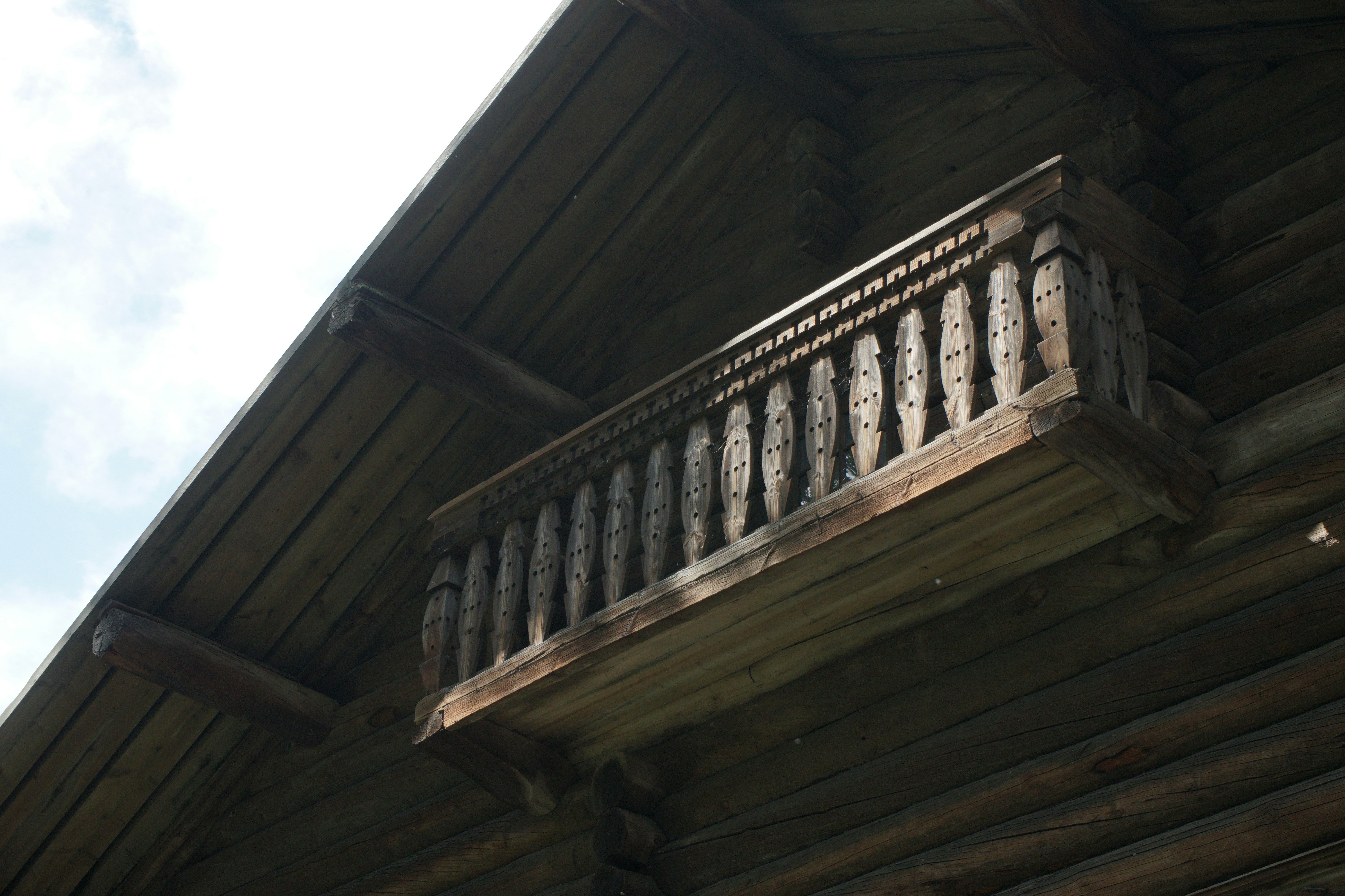 Weathered wooden balcony on a rustic cabin under diffused daylight