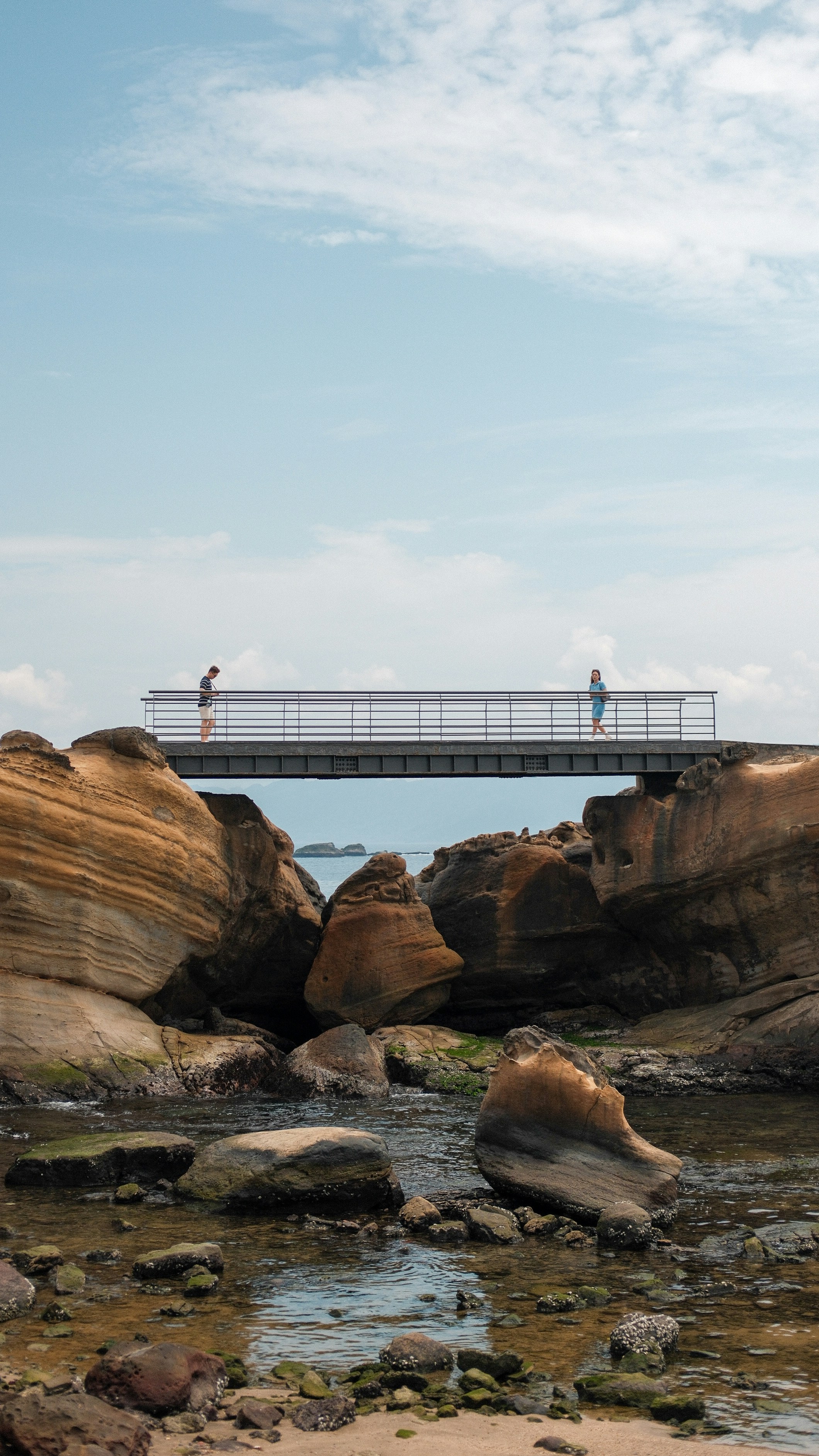 Bridge at the Tides: Two Figures on a Cliffside Walkway