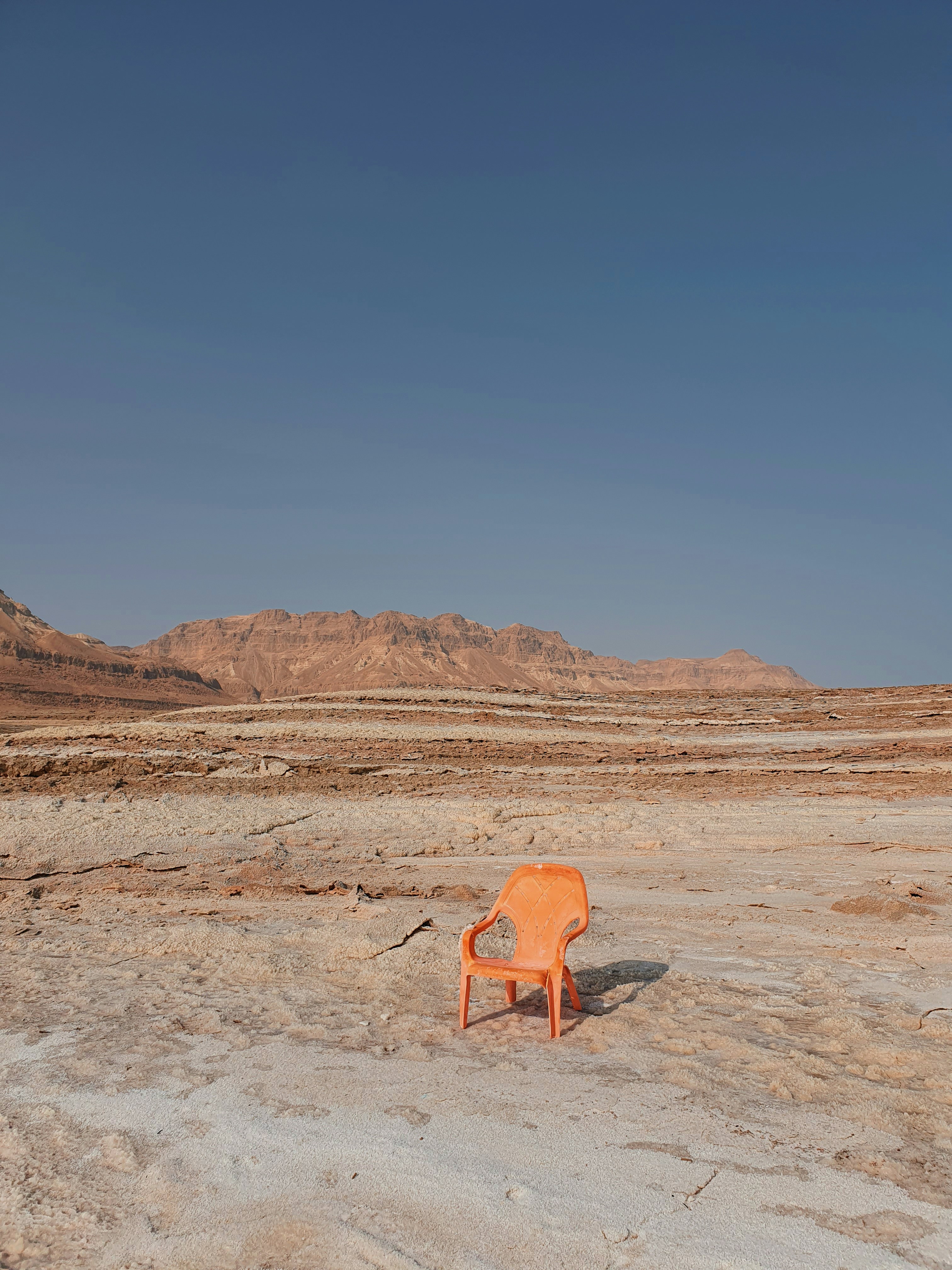 Desert Calm: An Orange Chair Against an Expansive Dune Horizon