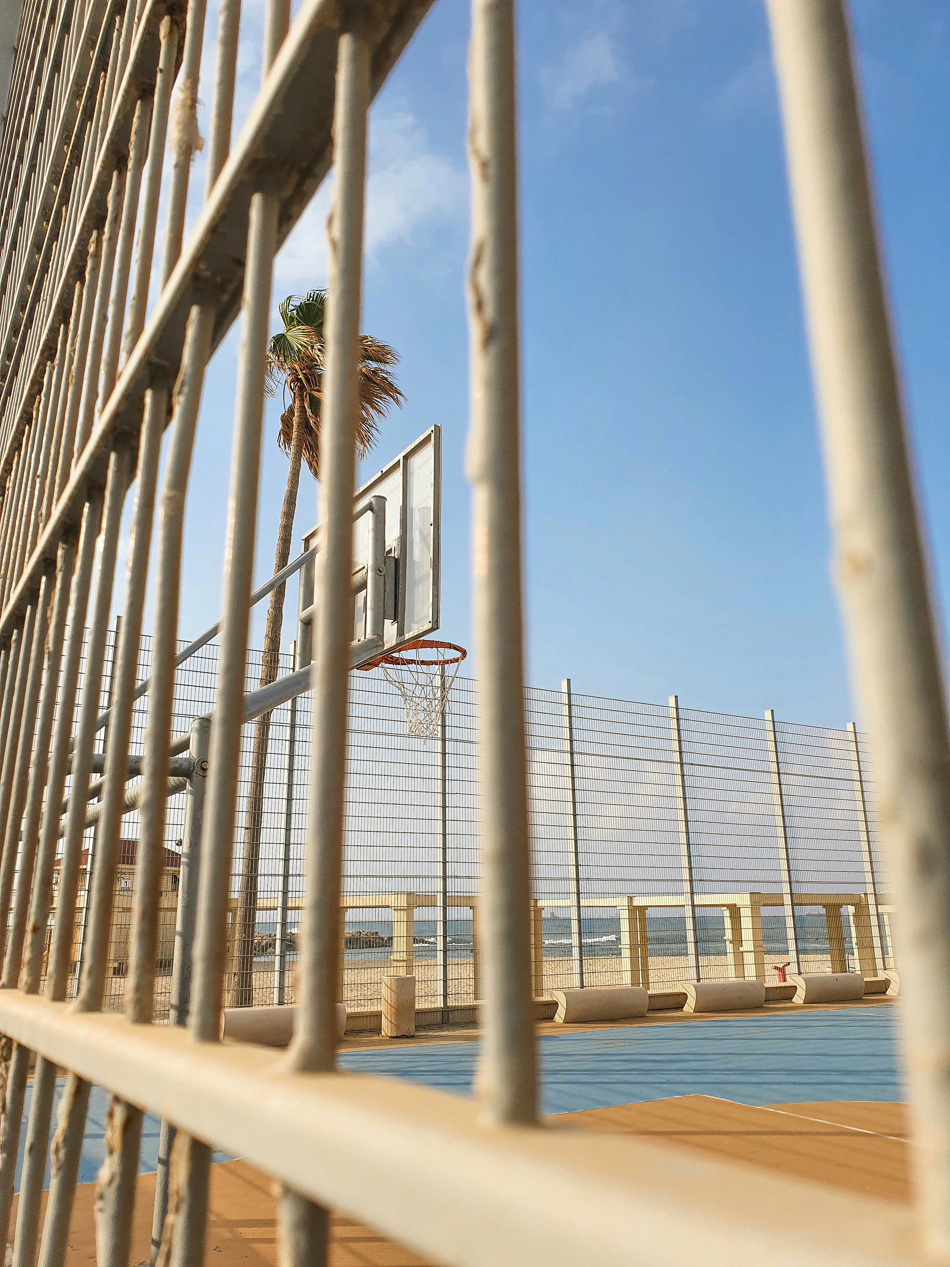 Basketball Court Through Weathered Railings on a Sunny Day