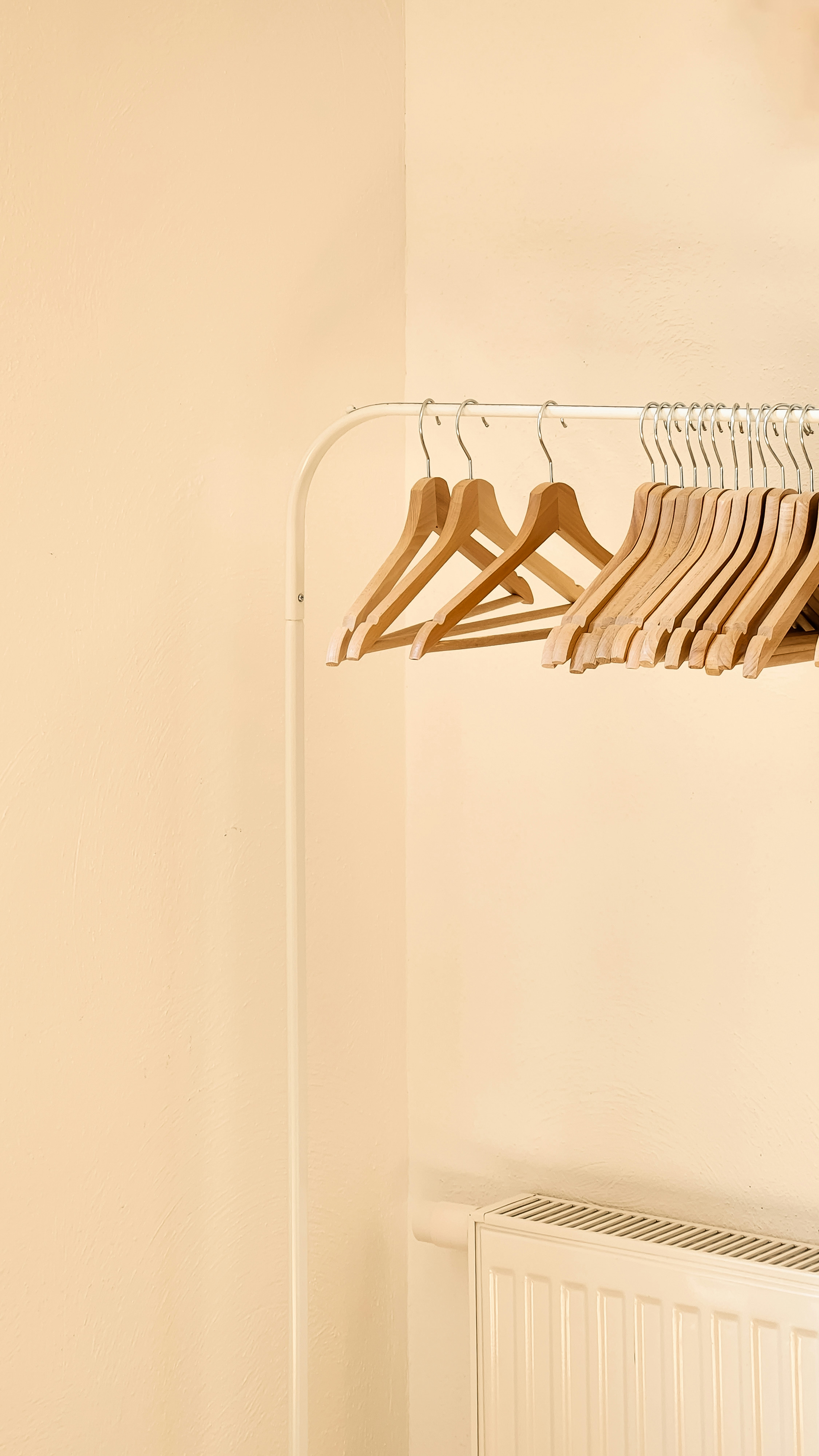 Minimal Wardrobe: A Row of Wooden Hangers on a Cream Rack