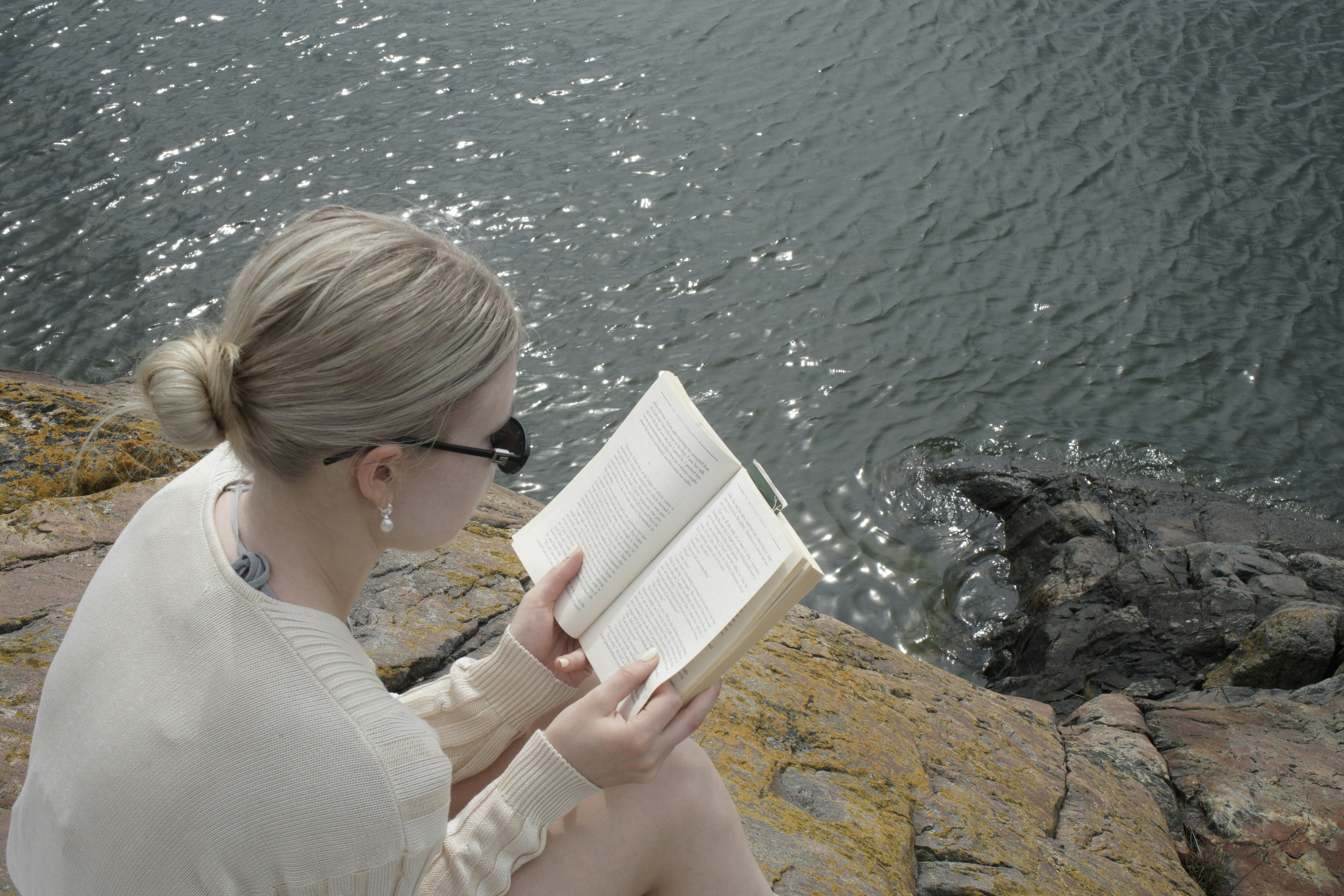 Quiet coastal reader by the lichen-streaked rocks