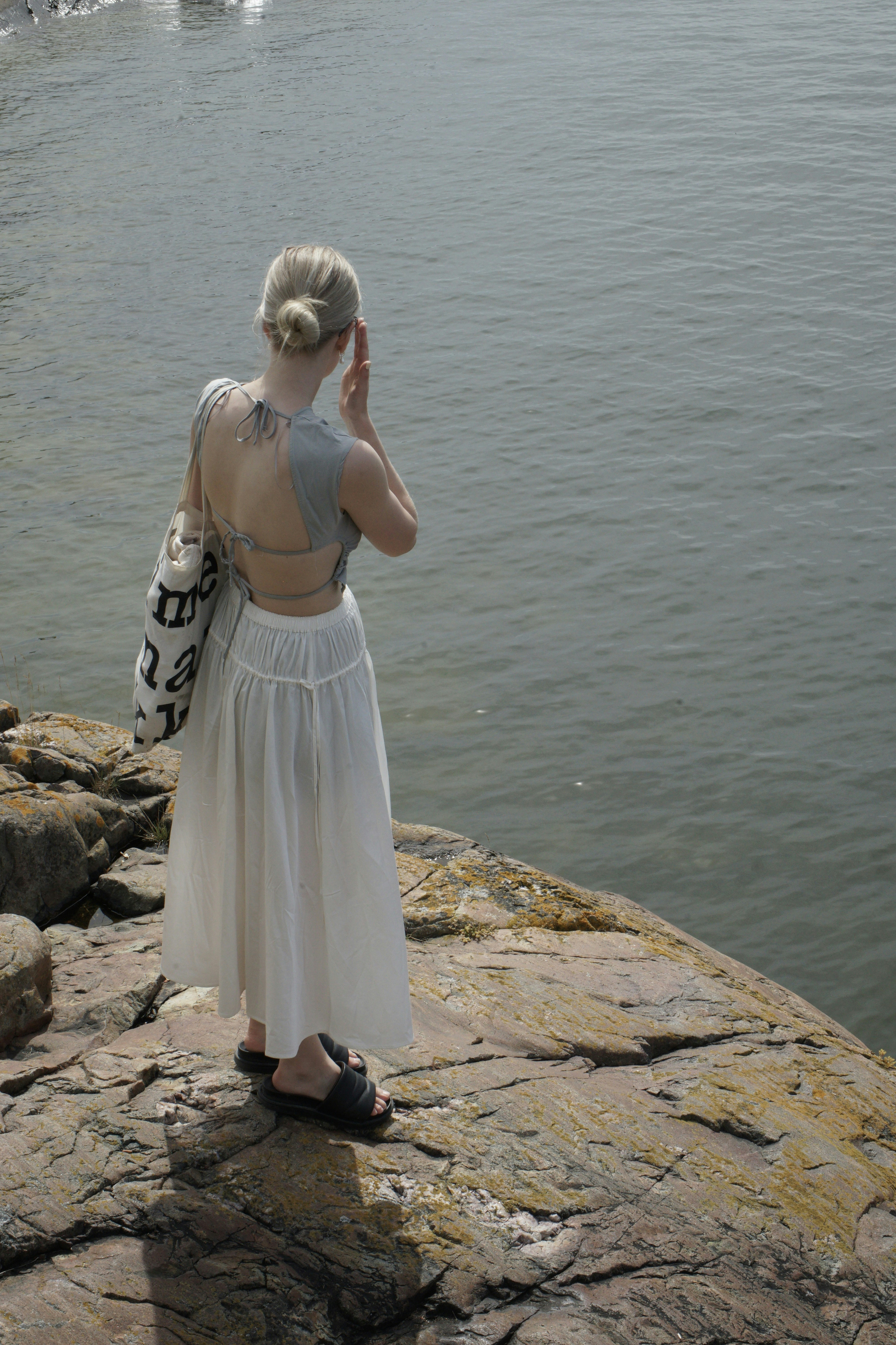 A Quiet Shoreline Moment: Woman in White Skirt by the Water