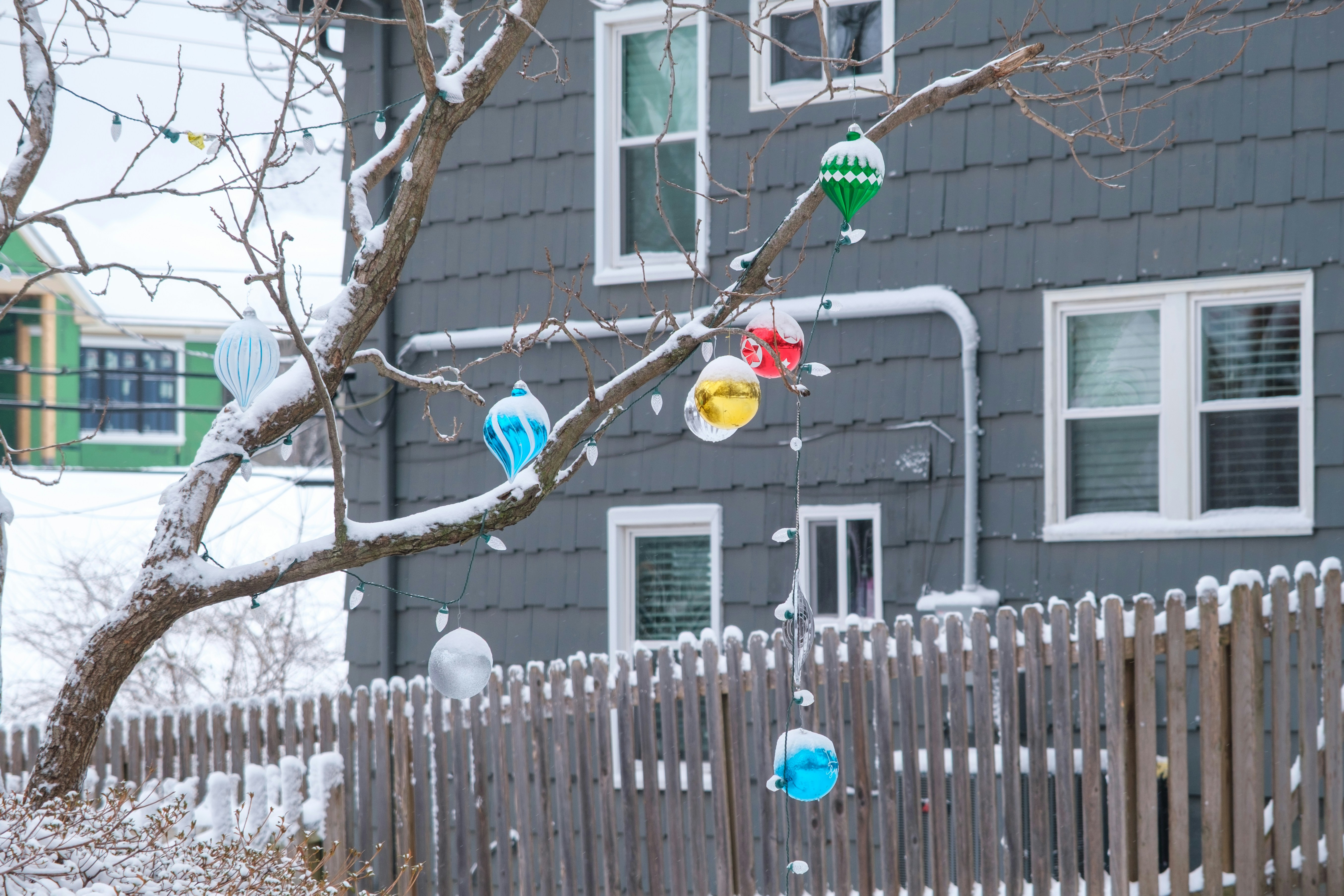 Lanterns in Winter: Colorful Ornaments Adorn a Snow-Dusted Fence