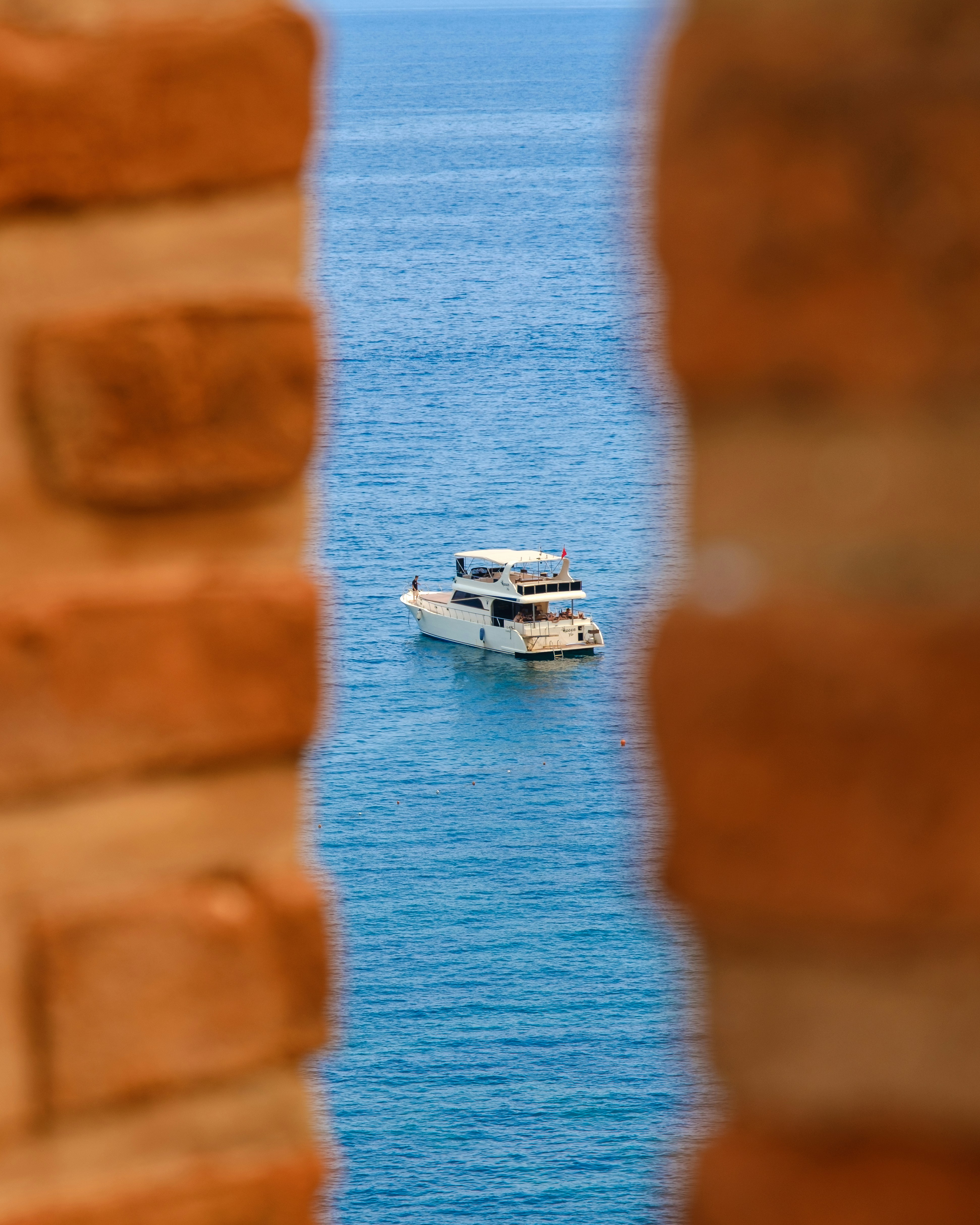 Boat gliding through a slot of sea between warm stone towers