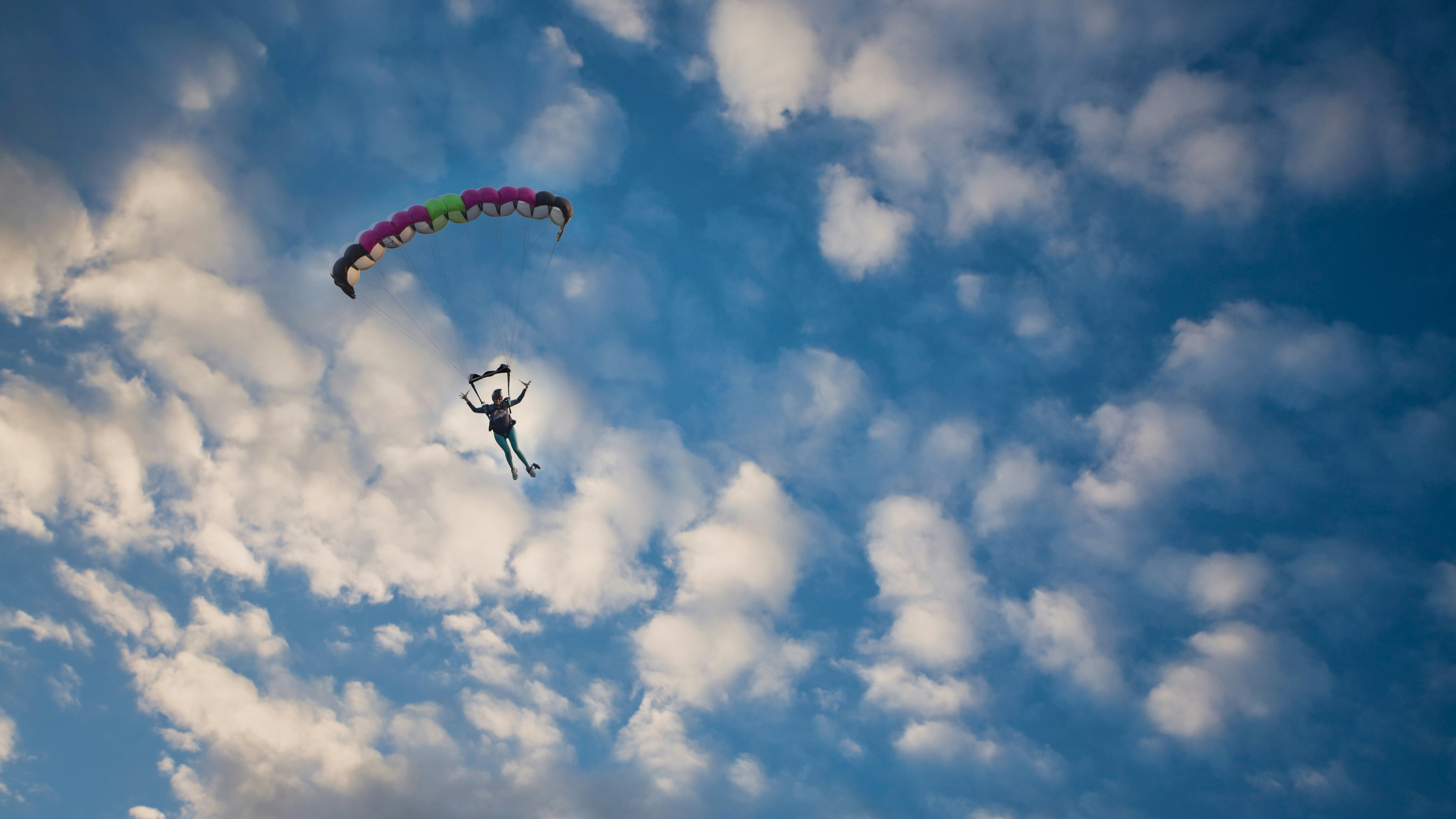 Aerial Acrobatics: Freefalling with a Colorful Parachute Against a Cloudscape