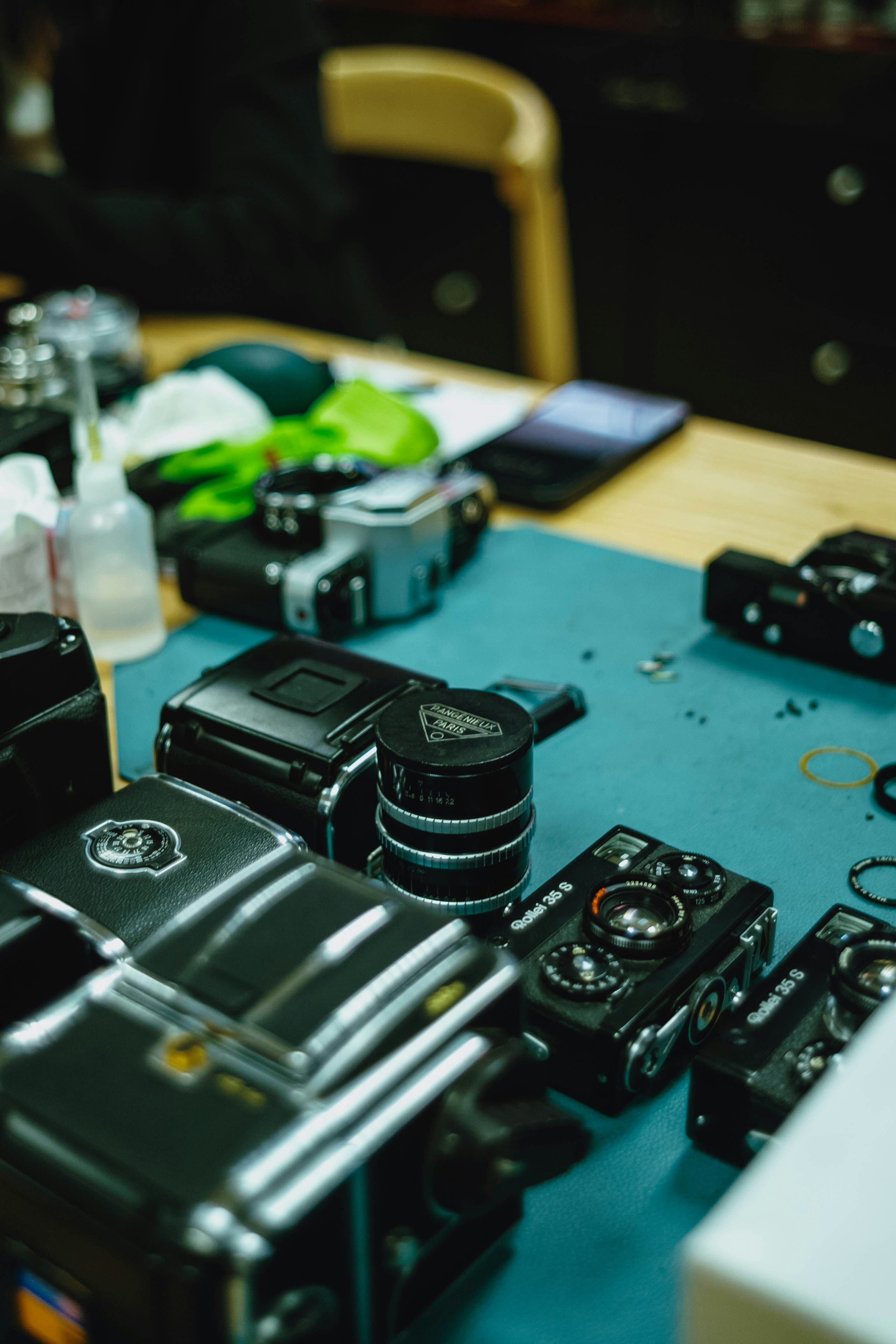 Vintage lenses and cameras spread across a cluttered worktable