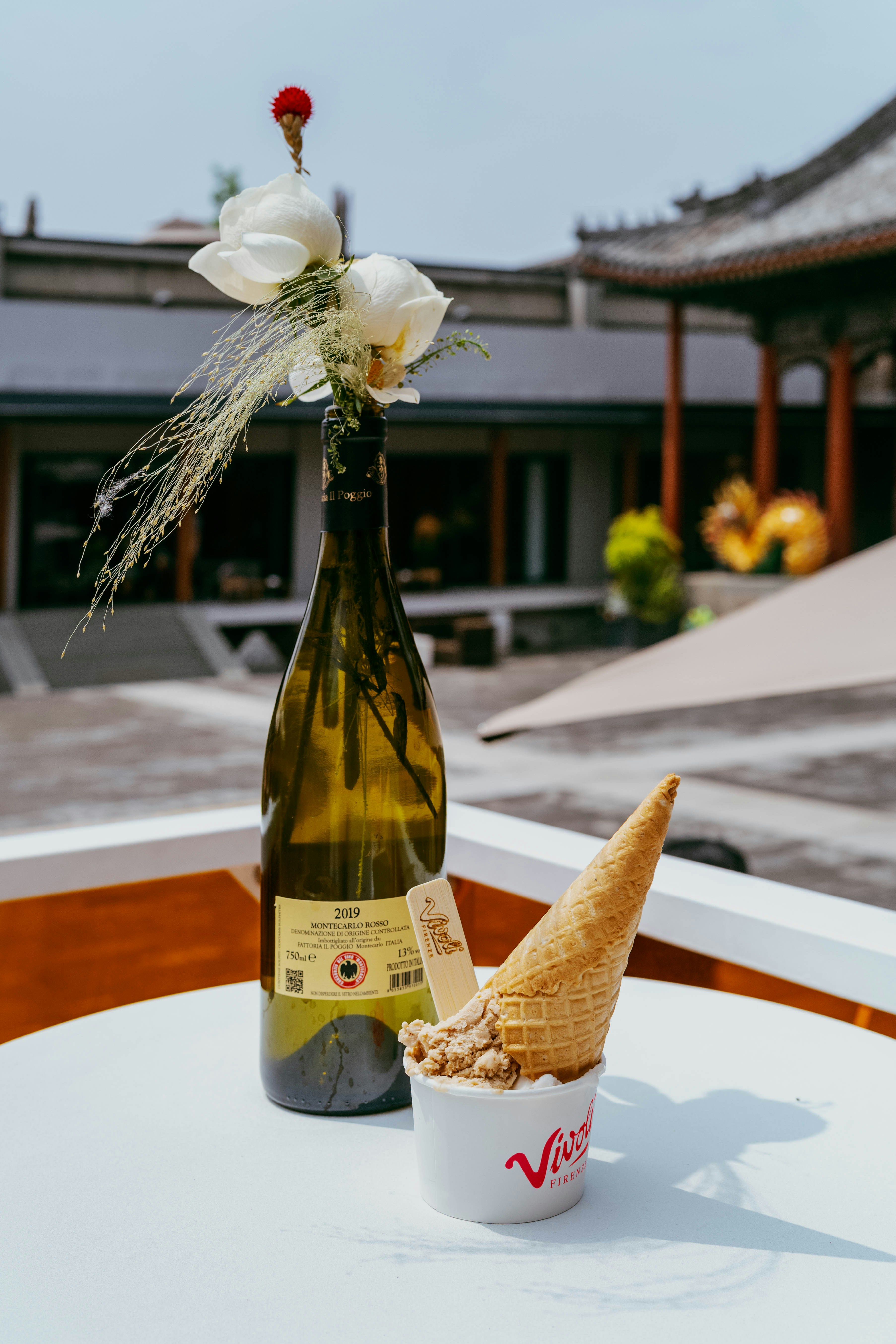 Still Life on a Terrace: White Flowers, Green Bottle, and a Vanilla Cone