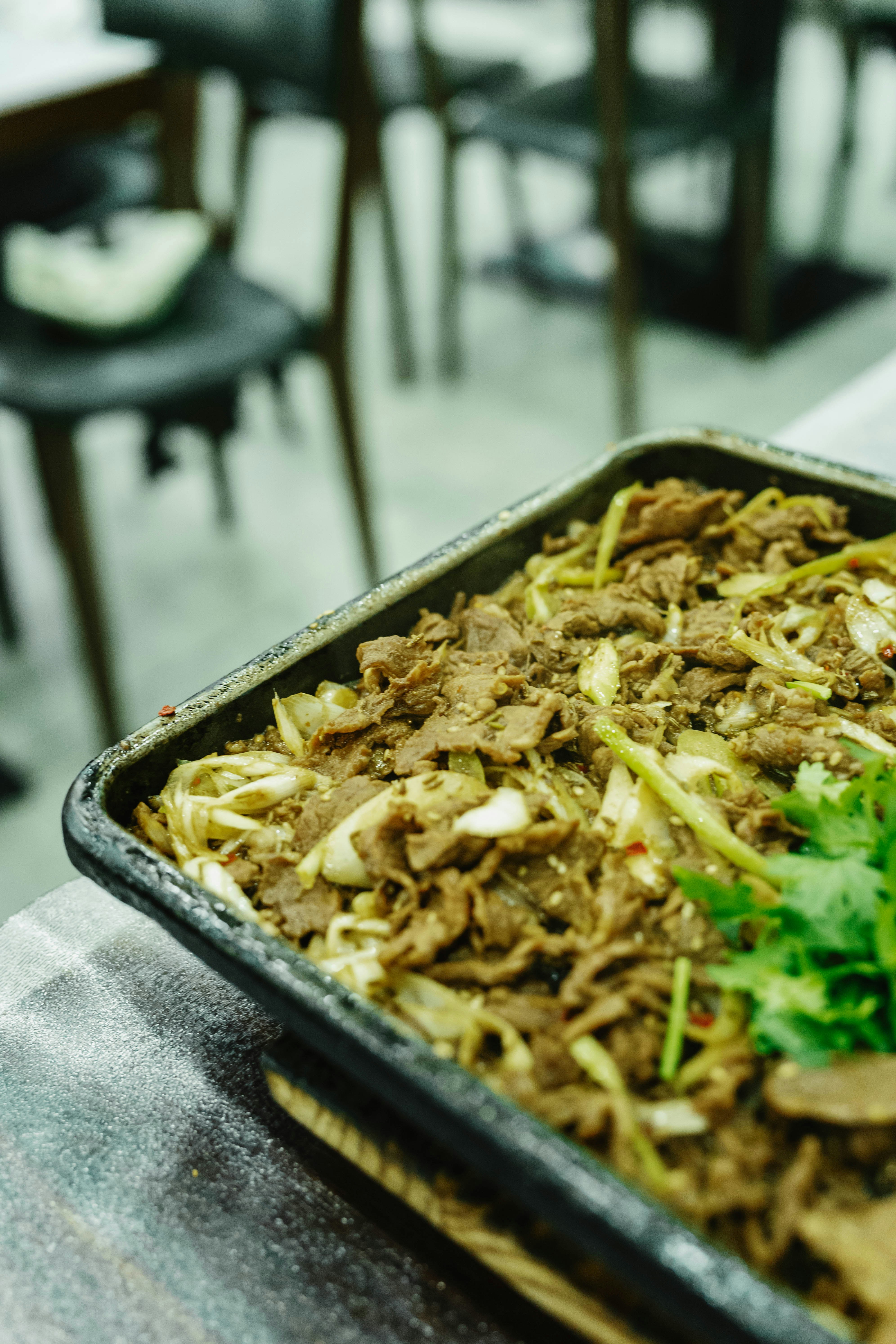 Sizzling skillet of beef and greens on a bustling cafe table