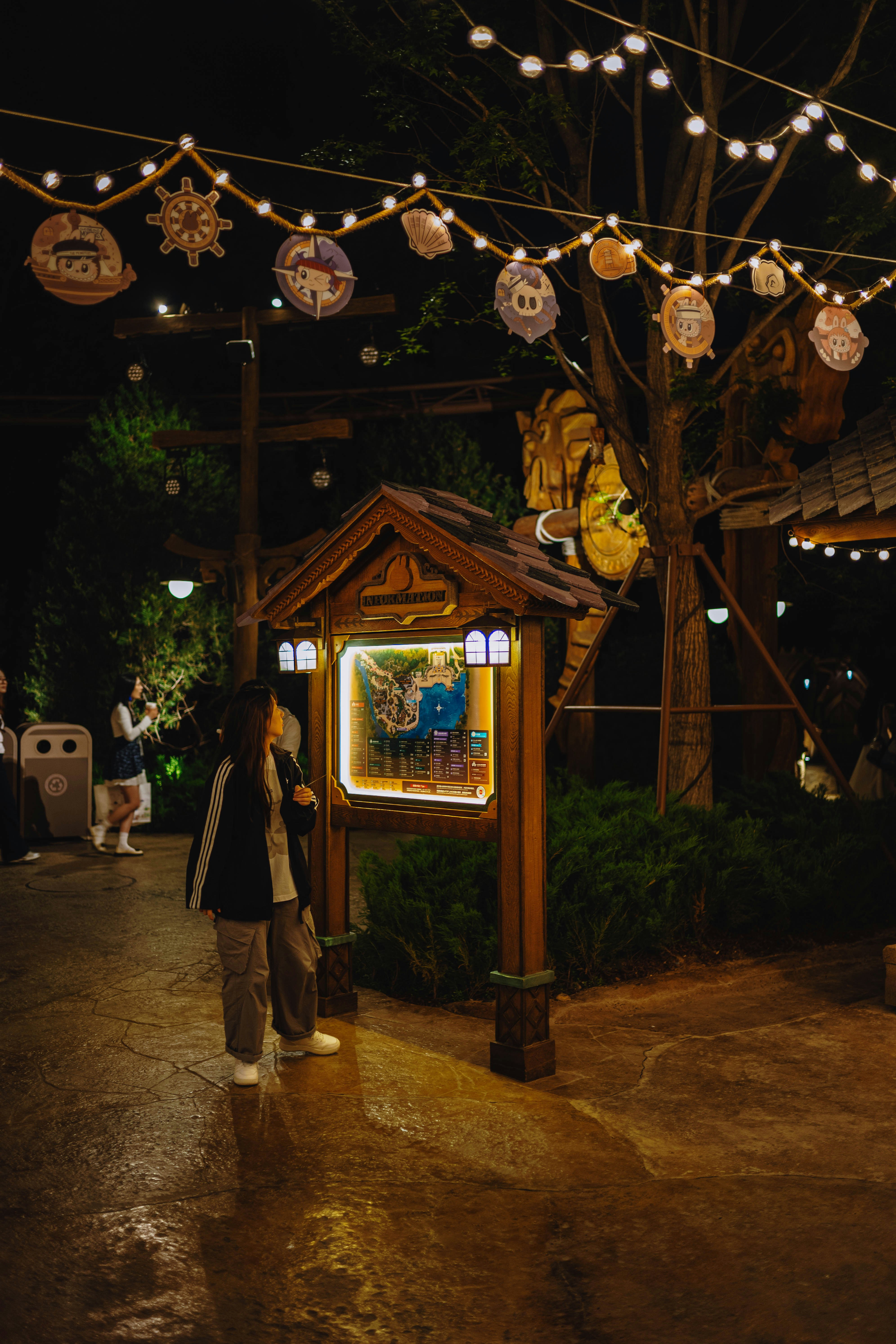Night Lanterns Over a Themed Park Post: A Couple Reads an Illuminated Map