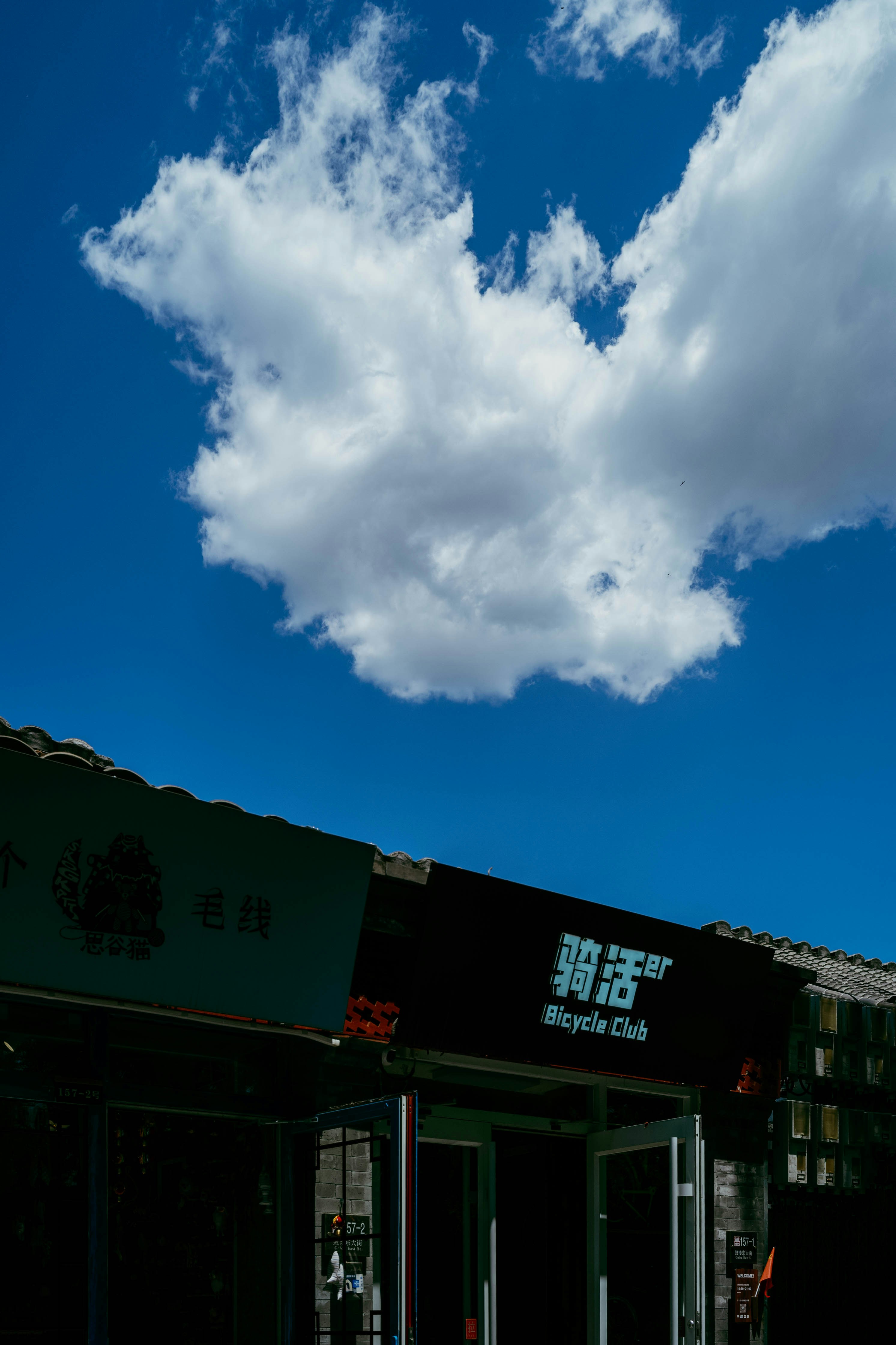 Cloud over the Bicycle Club storefront under a bright afternoon sky