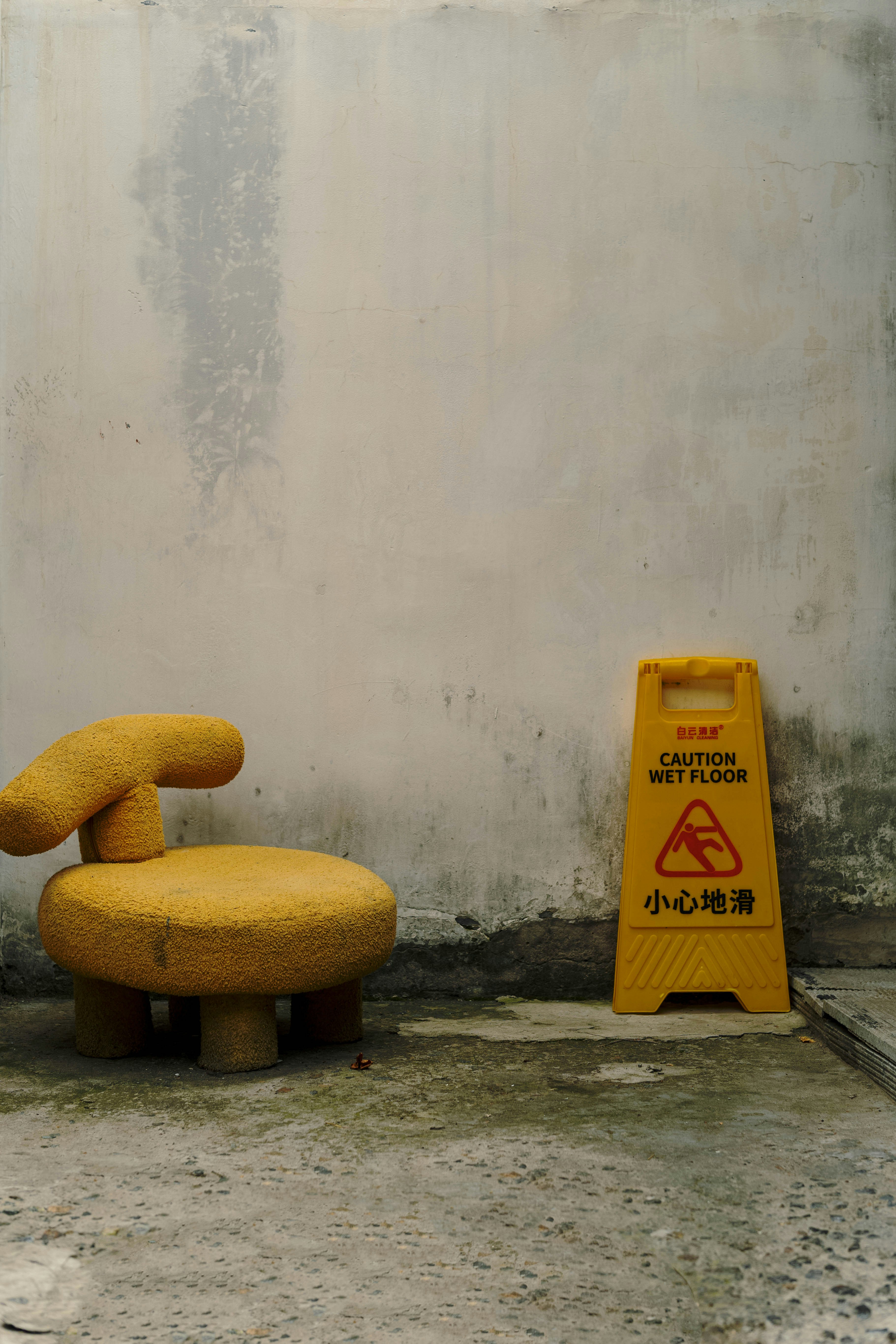 Yellow Seating and Wet Floor Warning in Quiet Concrete Scene