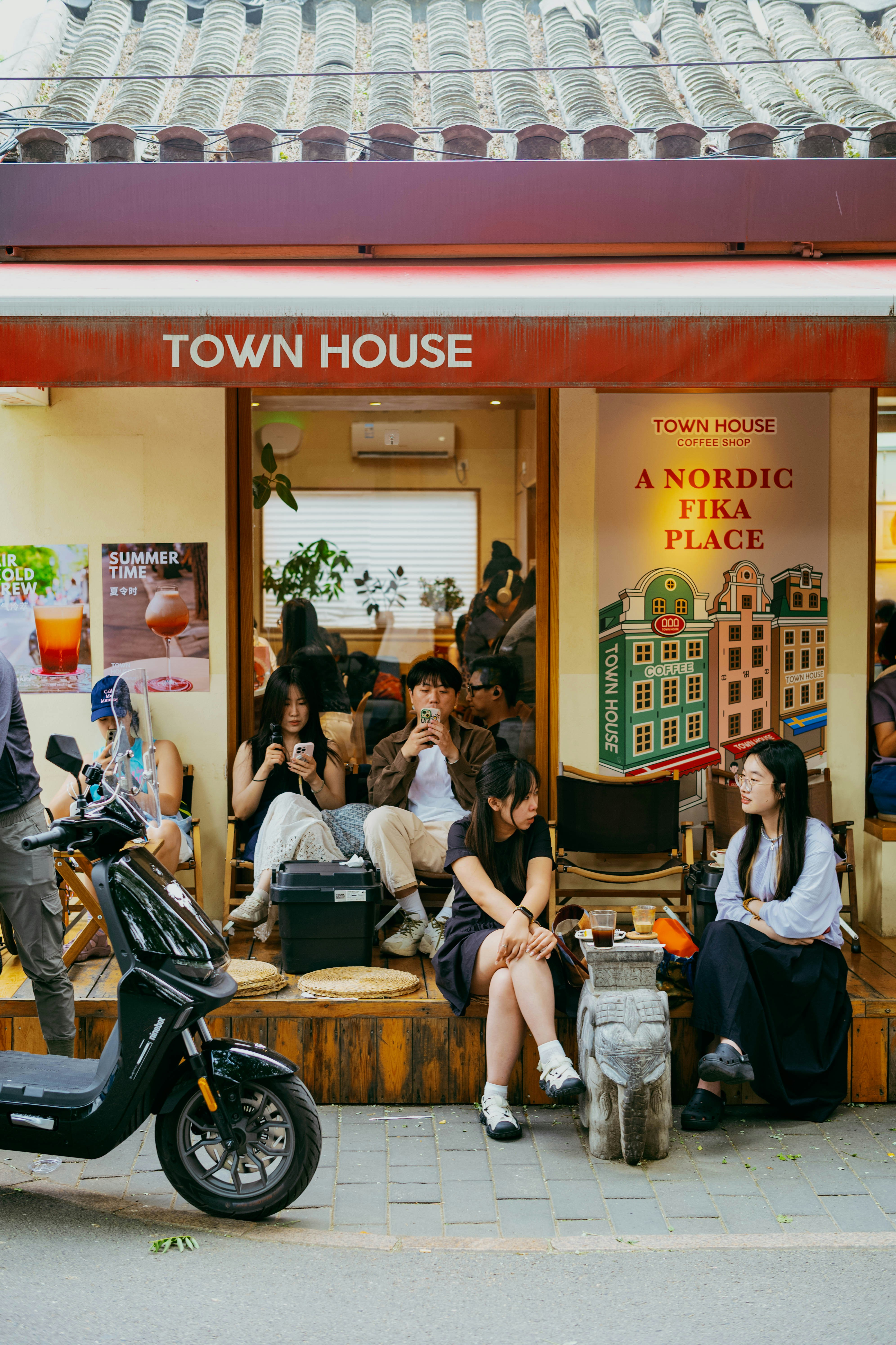 Bustling storefront with people seated outside Town House, capturing a casual moment of social gathering in a city street.