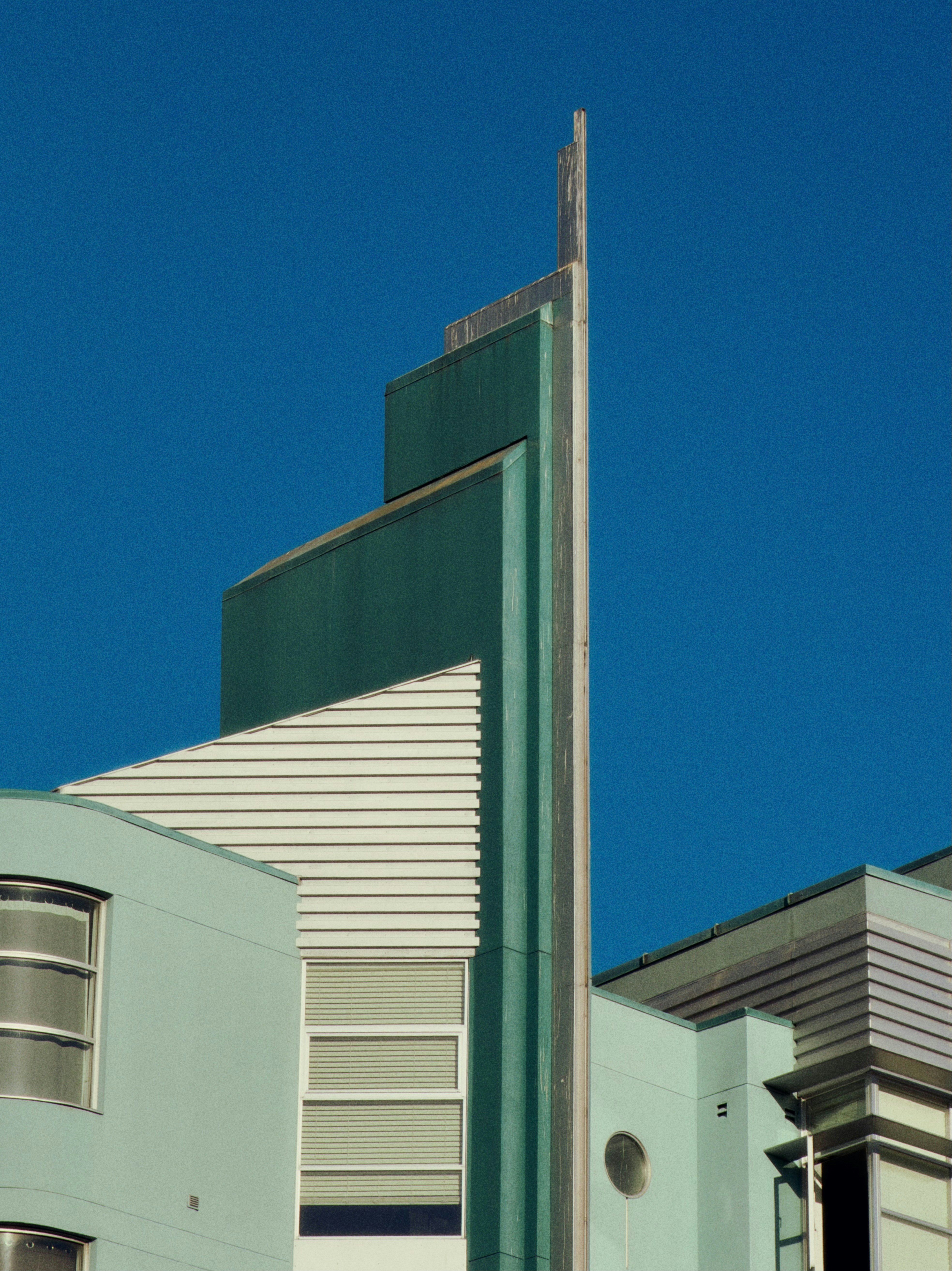 Vertical silhouette: teal architectural tower piercing a blue sky