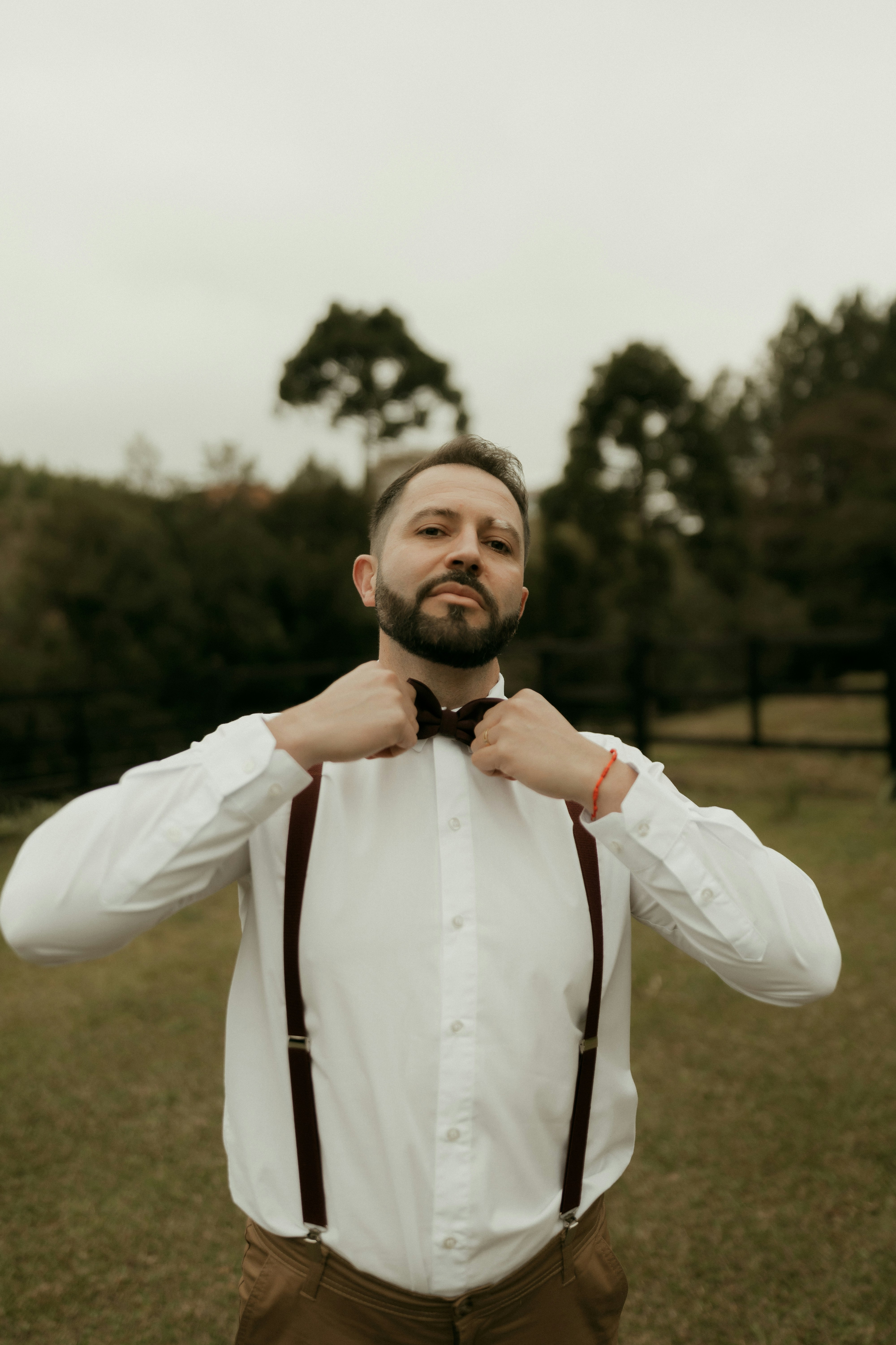 Gentleman in Field Tightens Bow Tie Under Soft Autumn Light